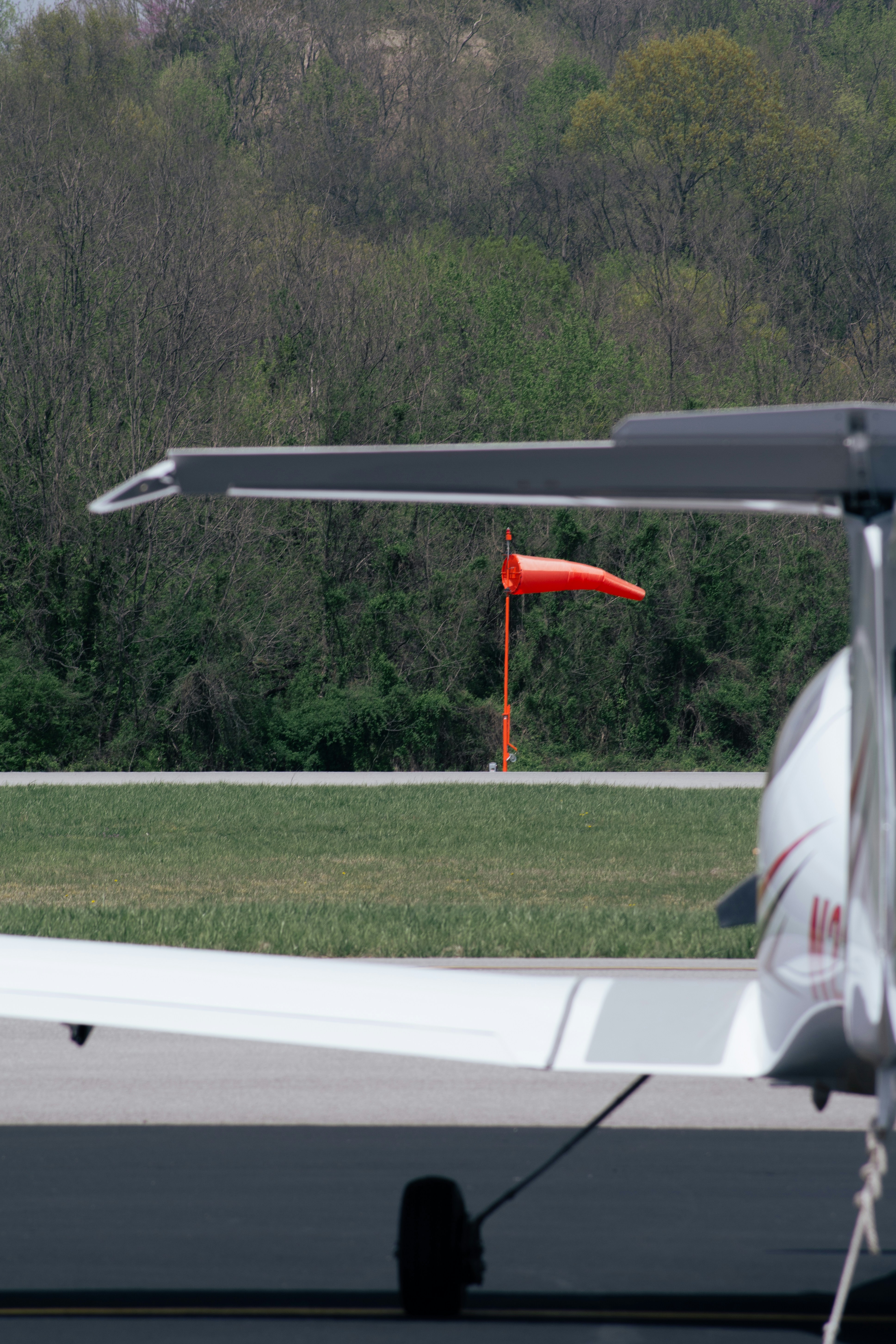 Red Windsock Framed by the Foreground Wing on a Quiet Airfield
