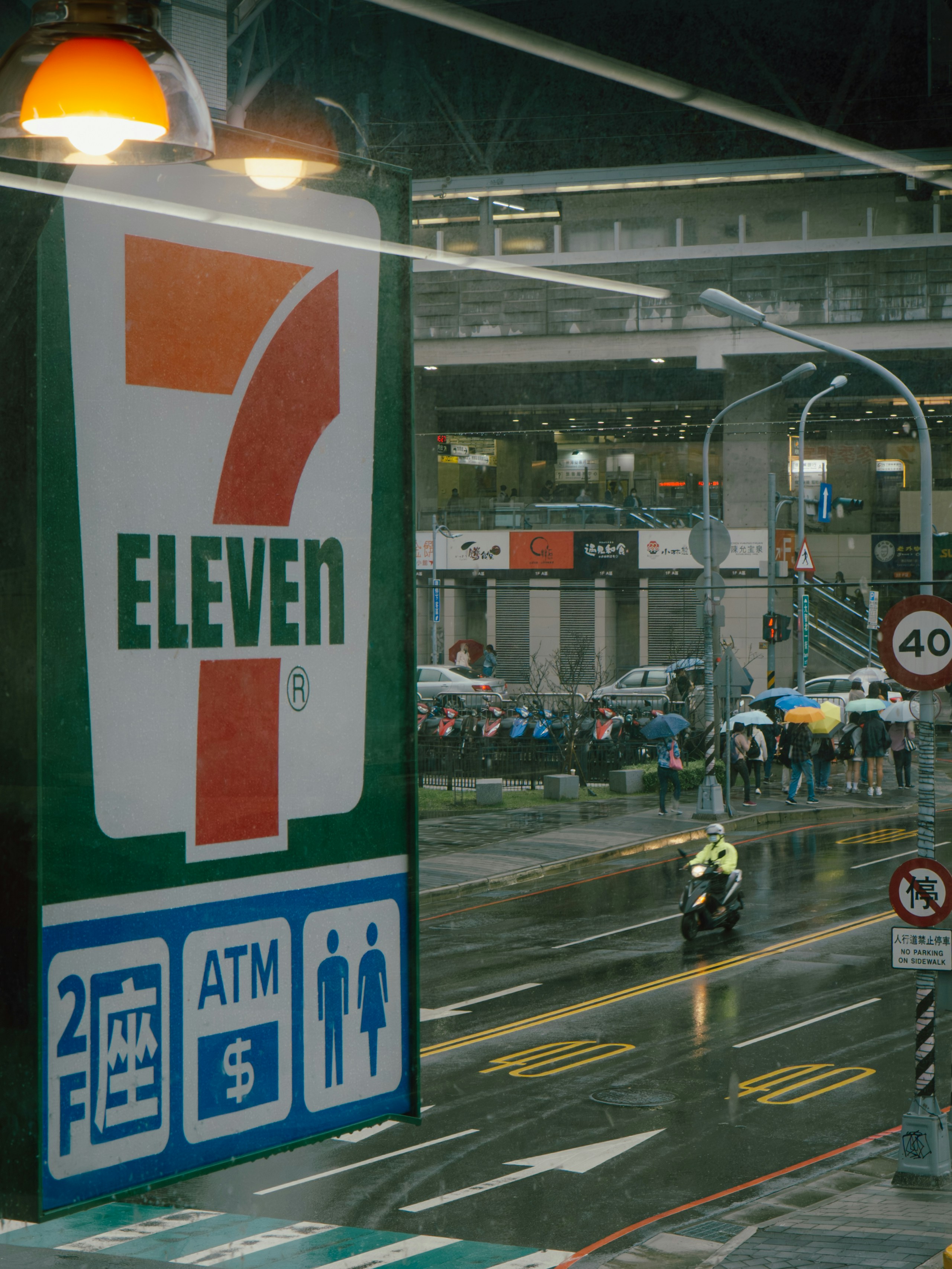 A seven eleven sign overlooks a rainy city street. photo – Free Car ...
