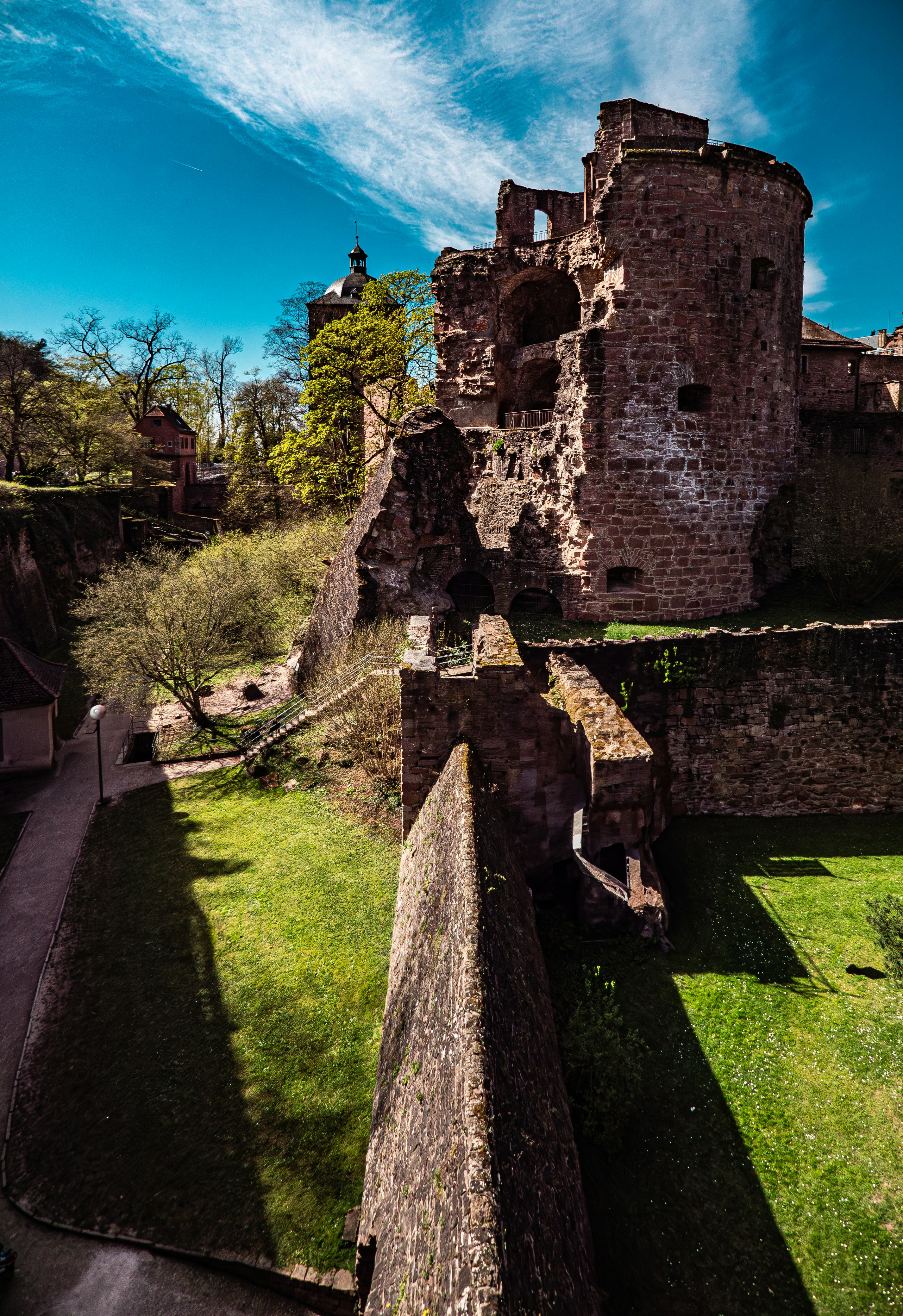 Ancient stone castle ruins with lush greenery and a bright blue sky.