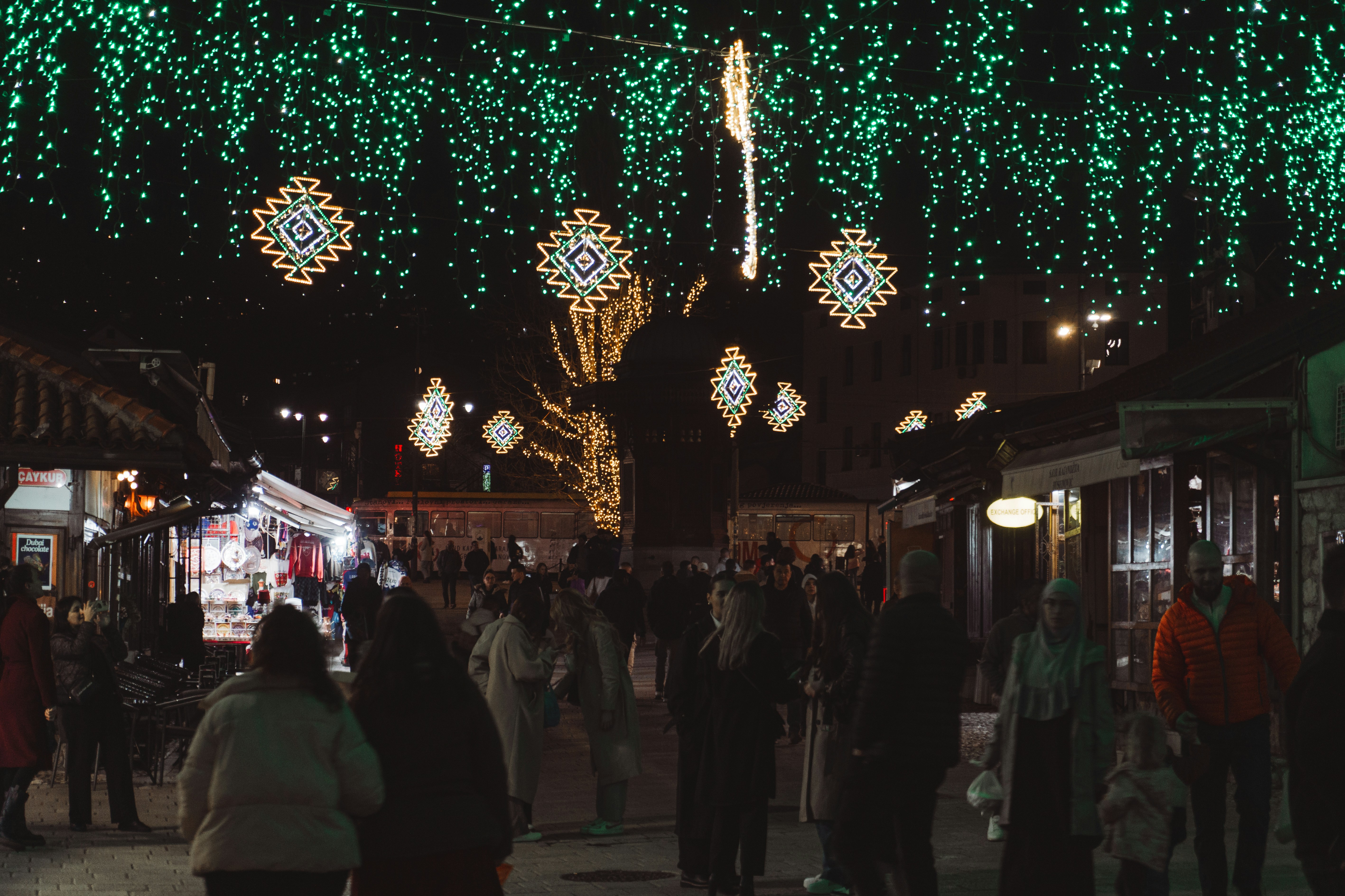 Festively decorated street bustling with people under a canopy of twinkling lights and ornamental stars.