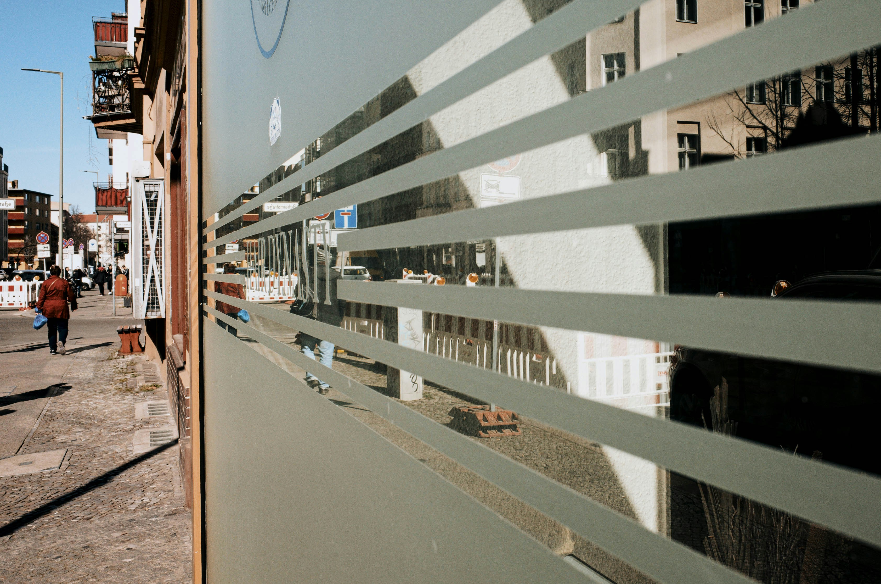 Glazed Stripes and a Quiet Pedestrian: A City Moment Through Glass
