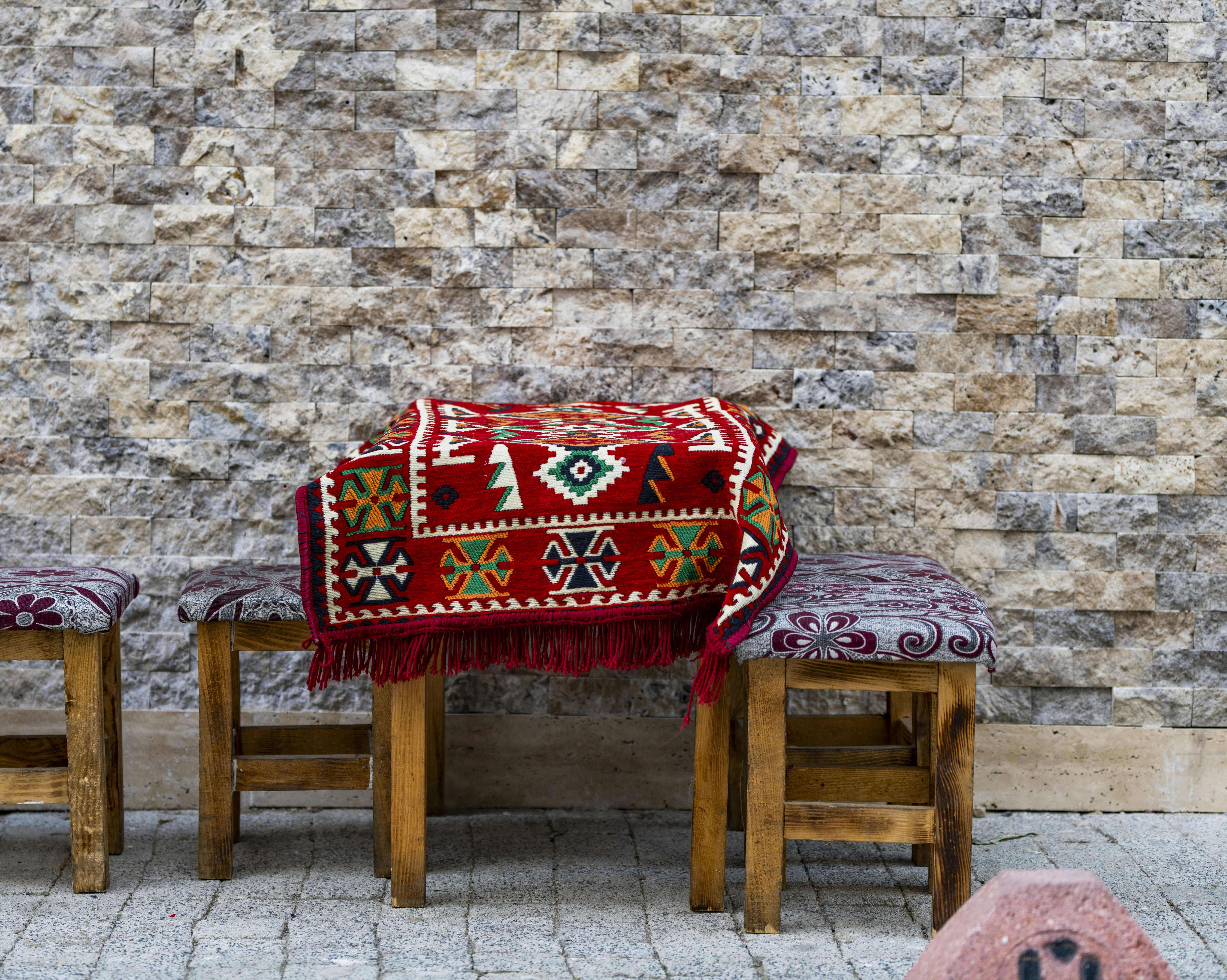 A red rug rests on wooden stools. photo – Free Art Image on Unsplash