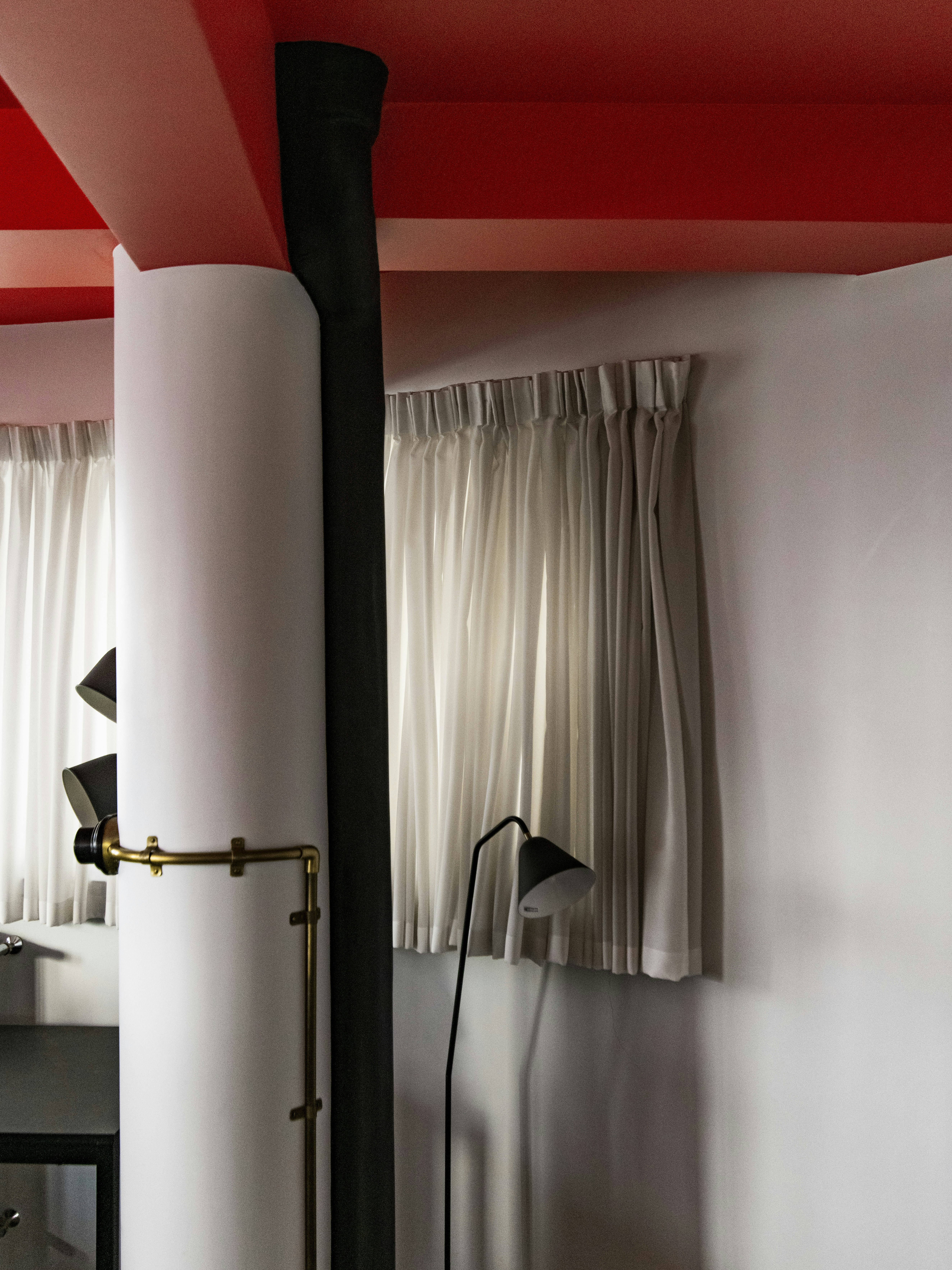 Minimalist Studio: White Column Framed by Red Ceiling and a Subtle Floor Lamp