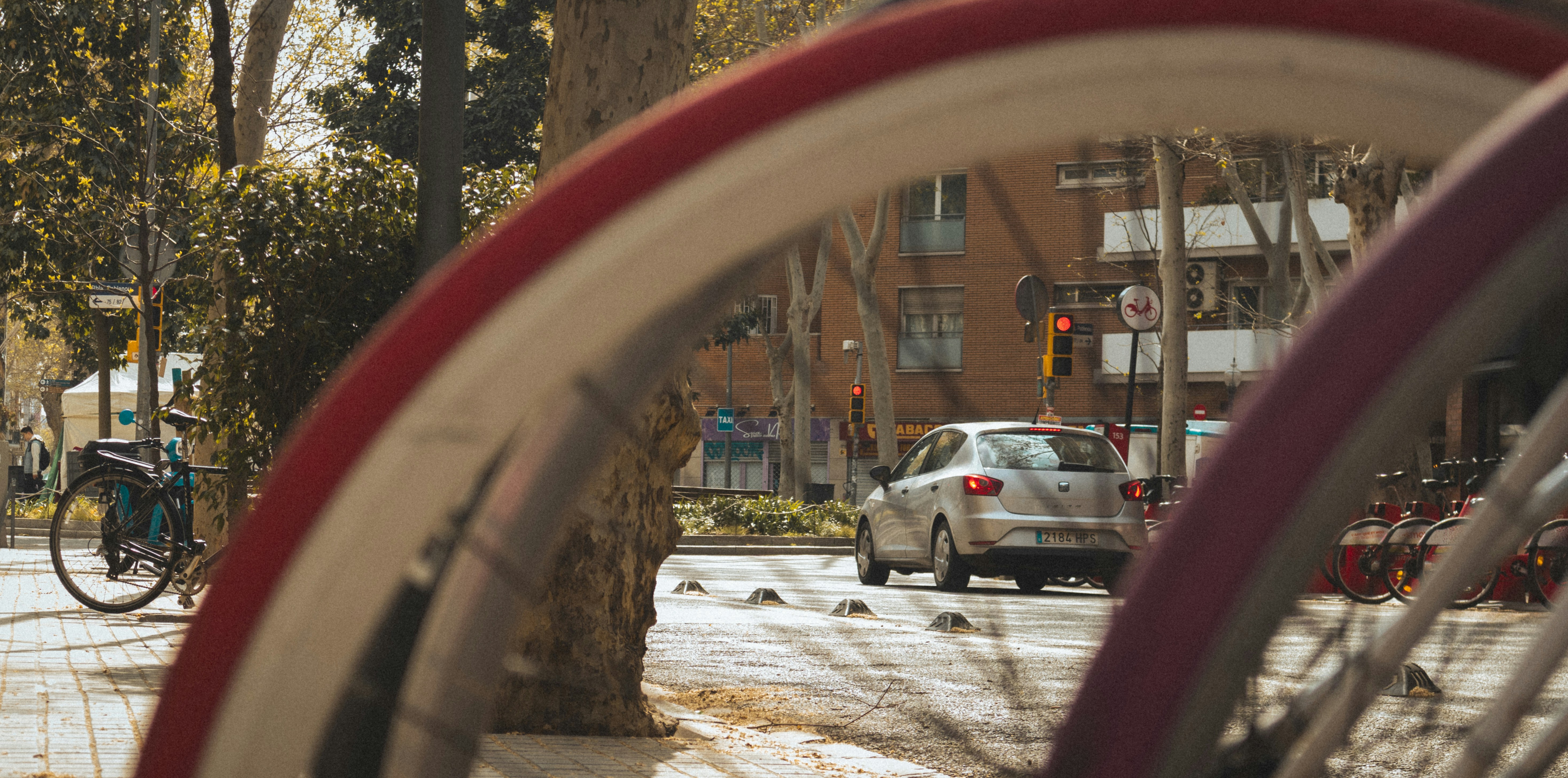 Focus on bicycle wheels with a city street and parked cars in the background.