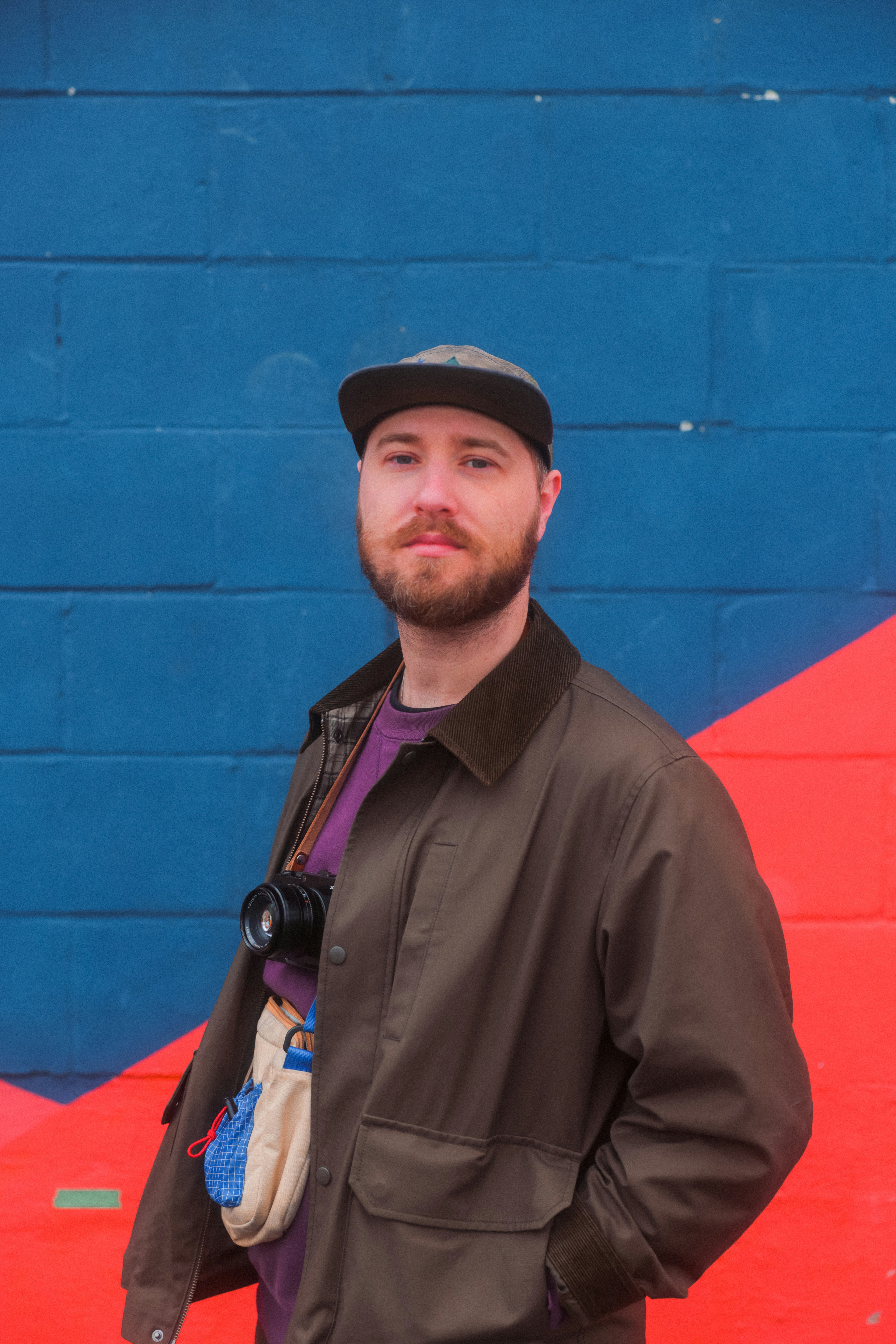 A man with a camera poses in front of a wall. photo – Free Portrait ...
