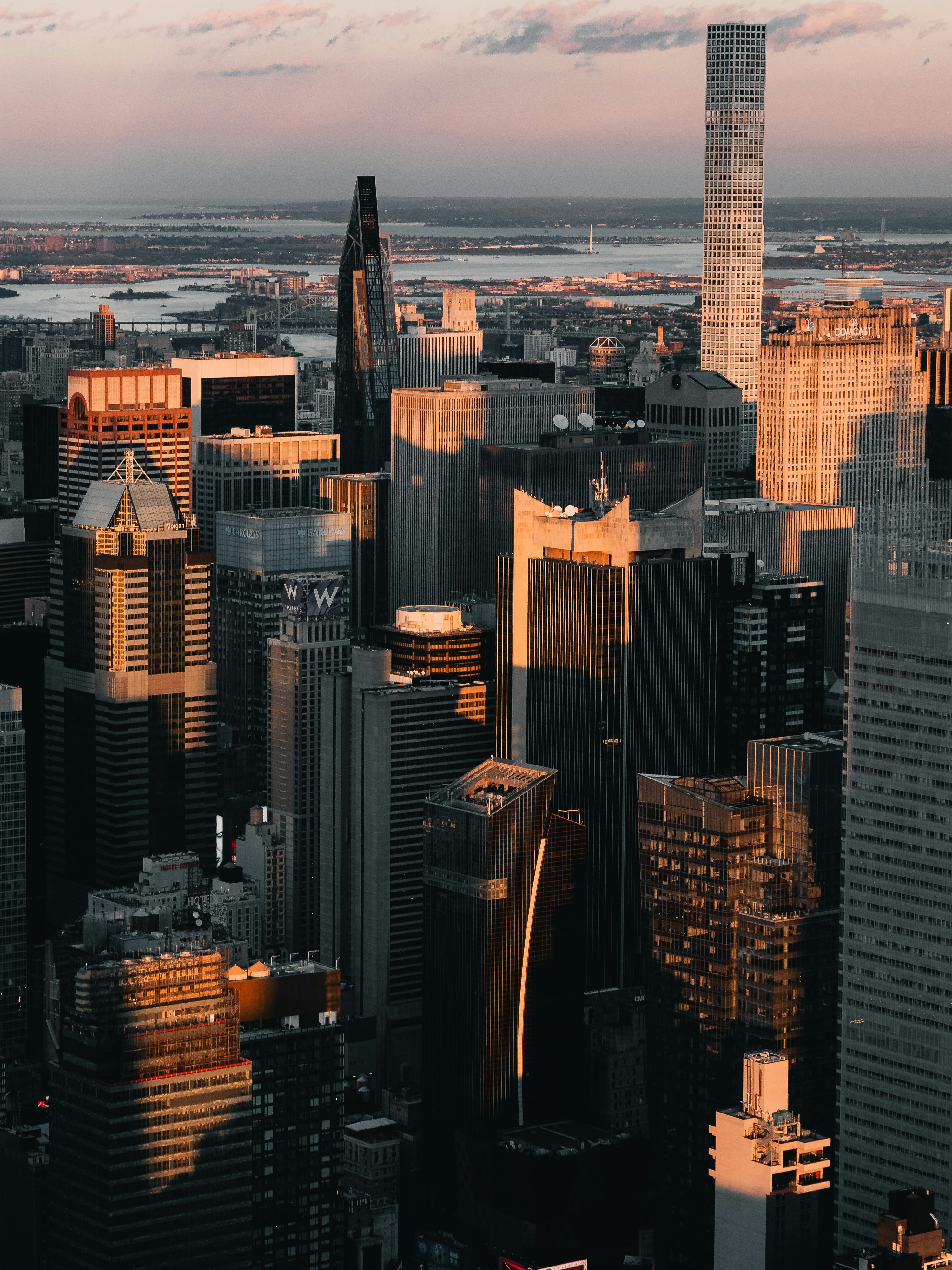 Skyscrapers bathed in warm sunset light, casting long shadows across a dense cityscape.