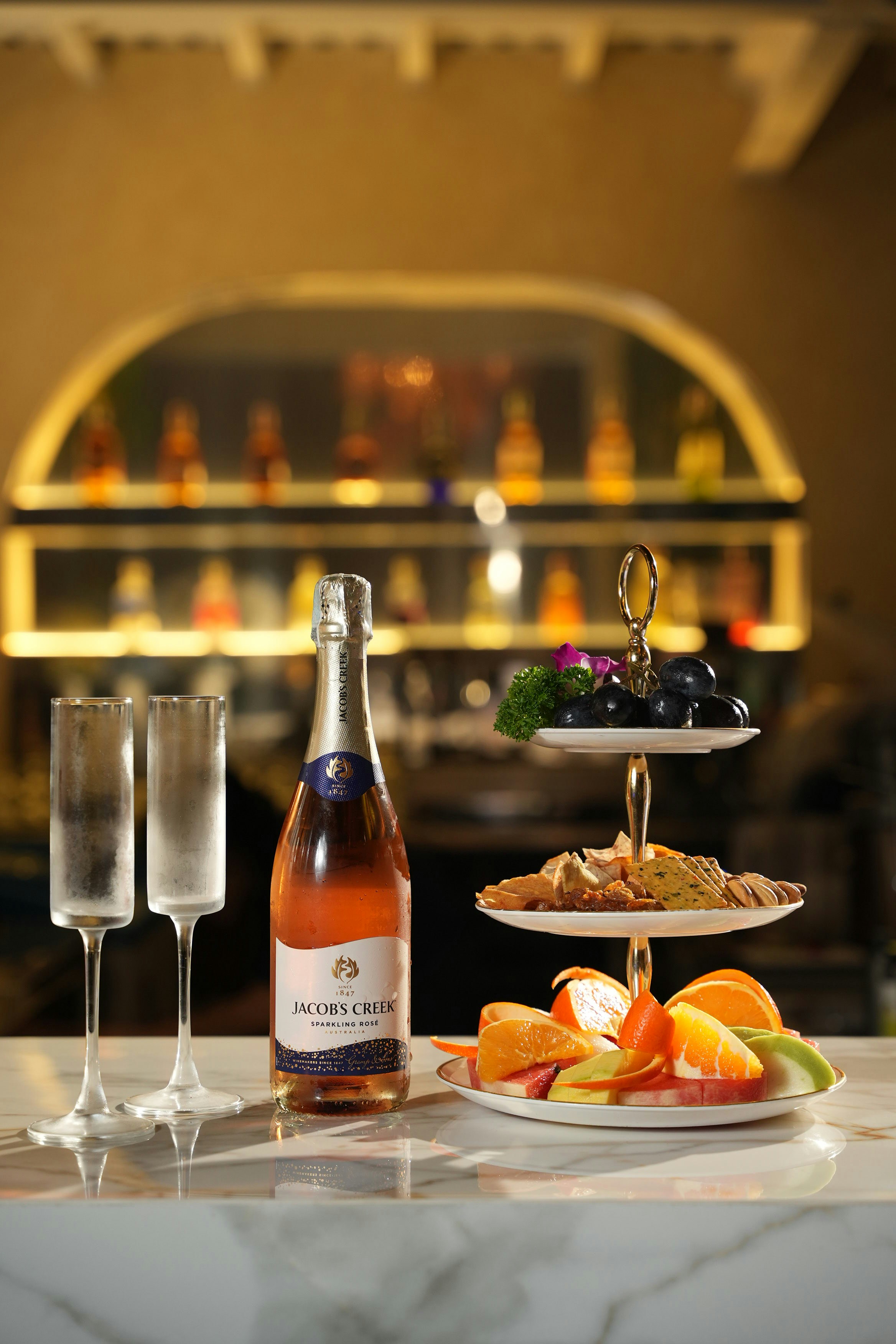 Chilled sparkling wine with fresh fruit and pastries on a marble counter.