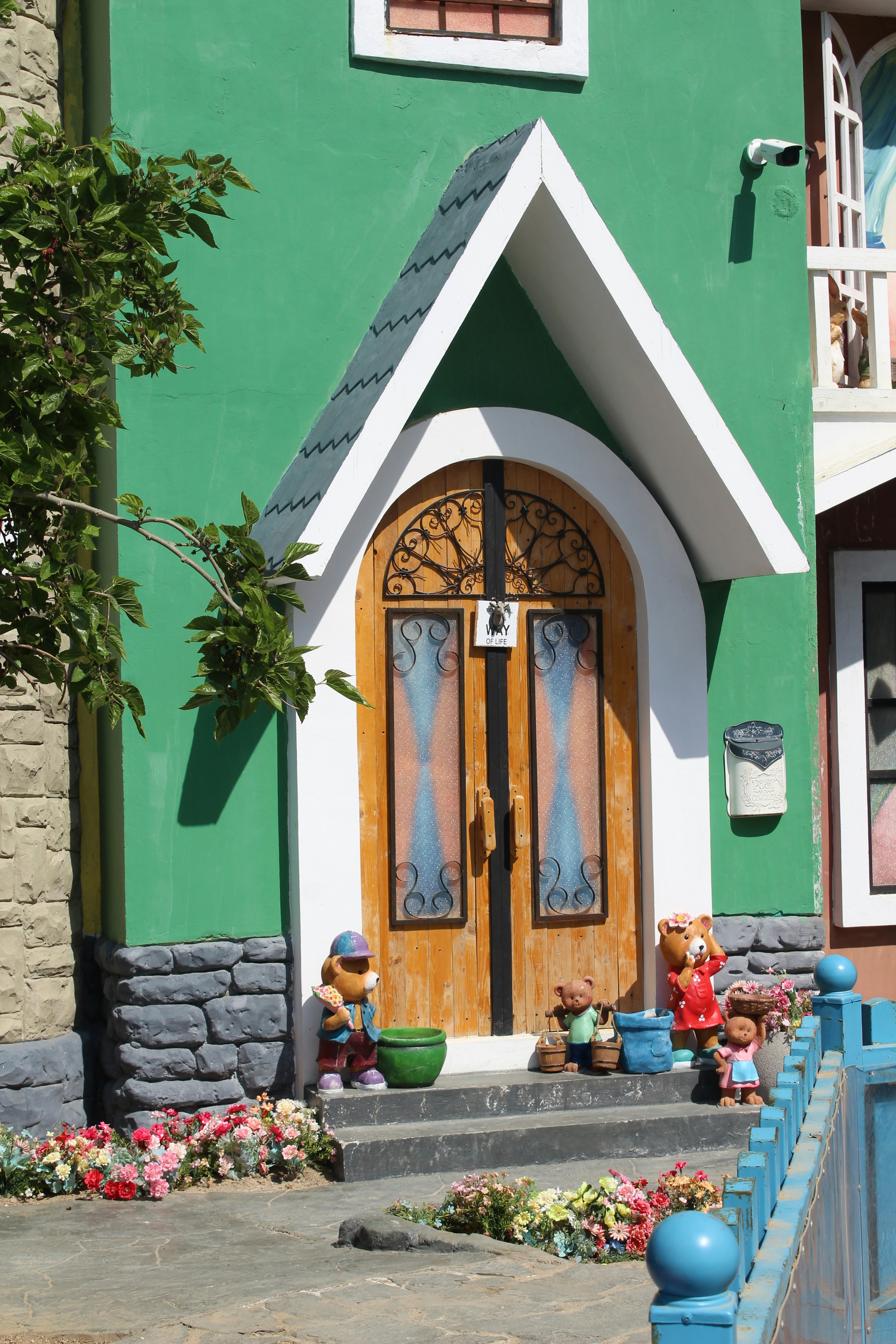Verdant Doorway Parade: A Green Façade Framed by Tiny Garden Figures