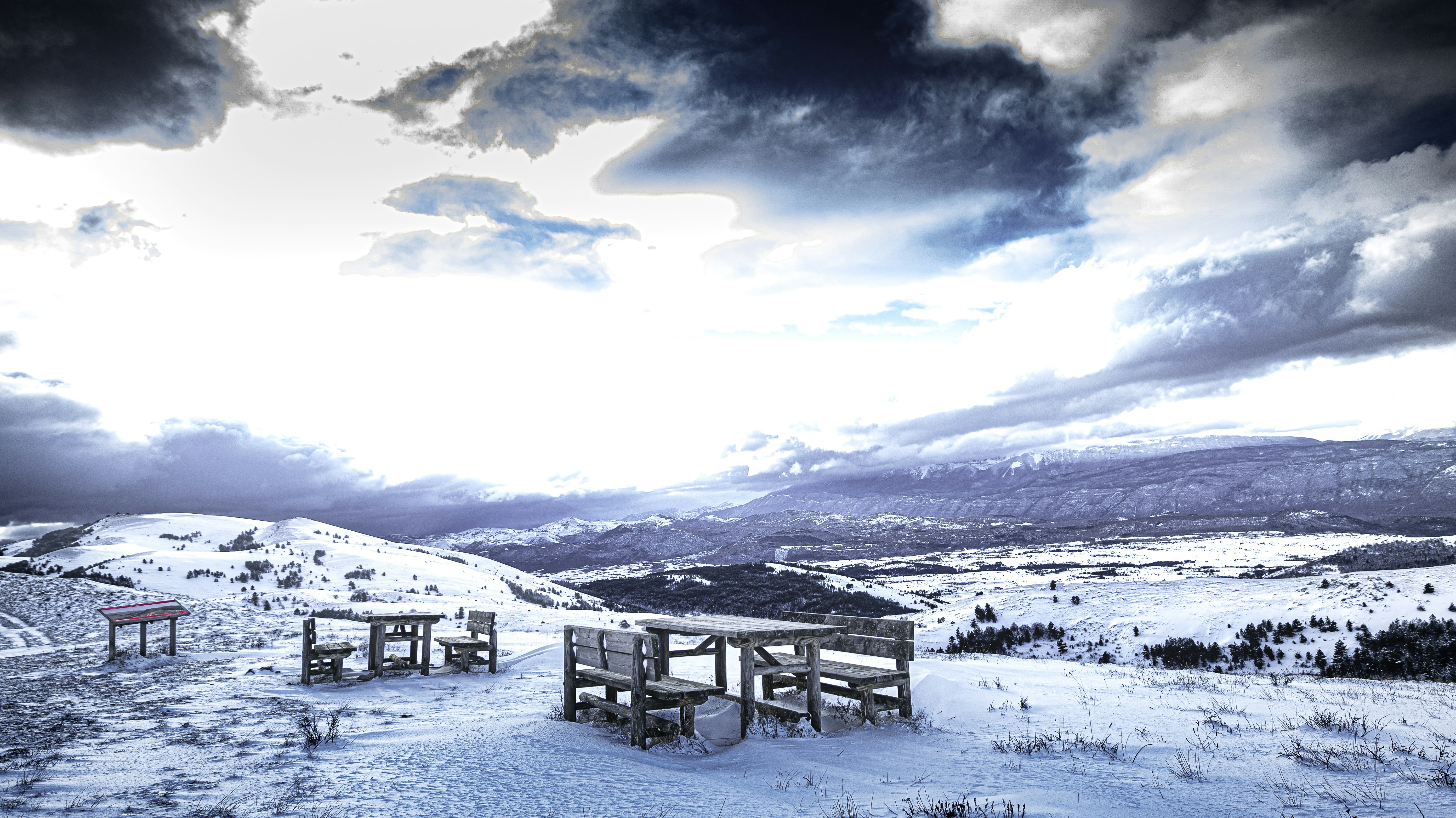 Snowbound Lookout: Weathered Benches Beneath a Turbulent Sky