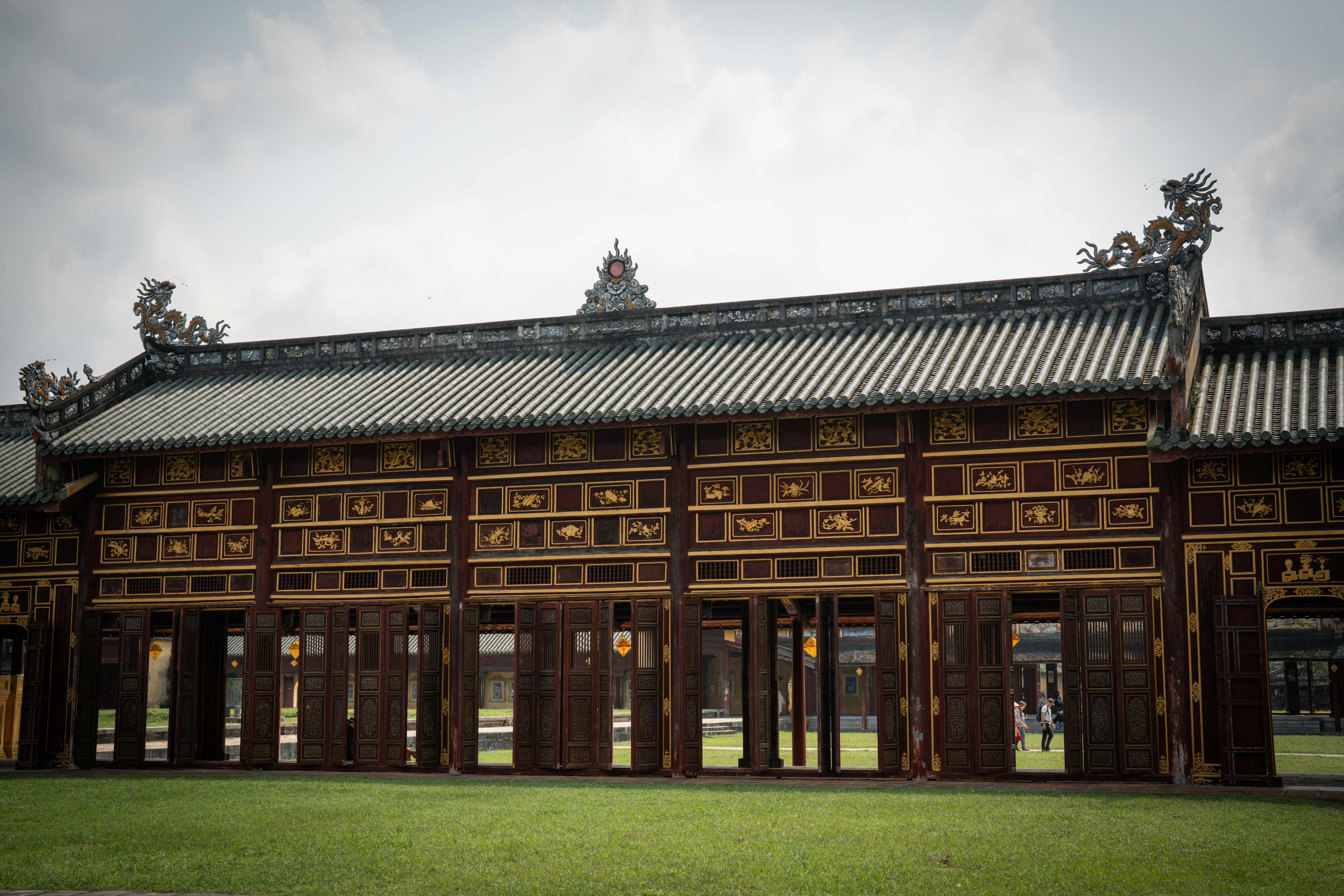 Ornate Timber Gate with Gold Inlays Framed by a Lush Lawn