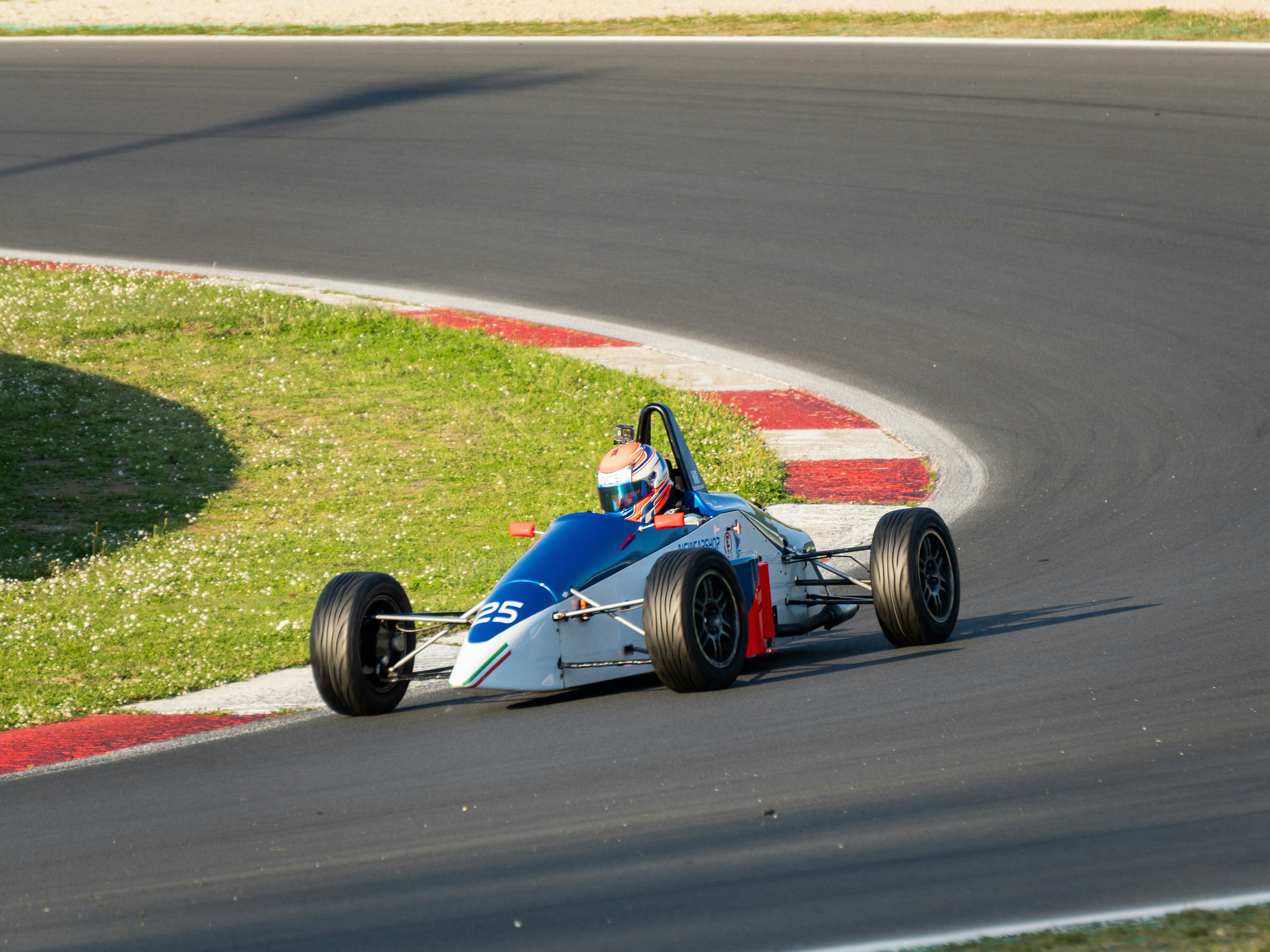 Single-seater race car navigating a sharp corner on a racing track under clear skies.