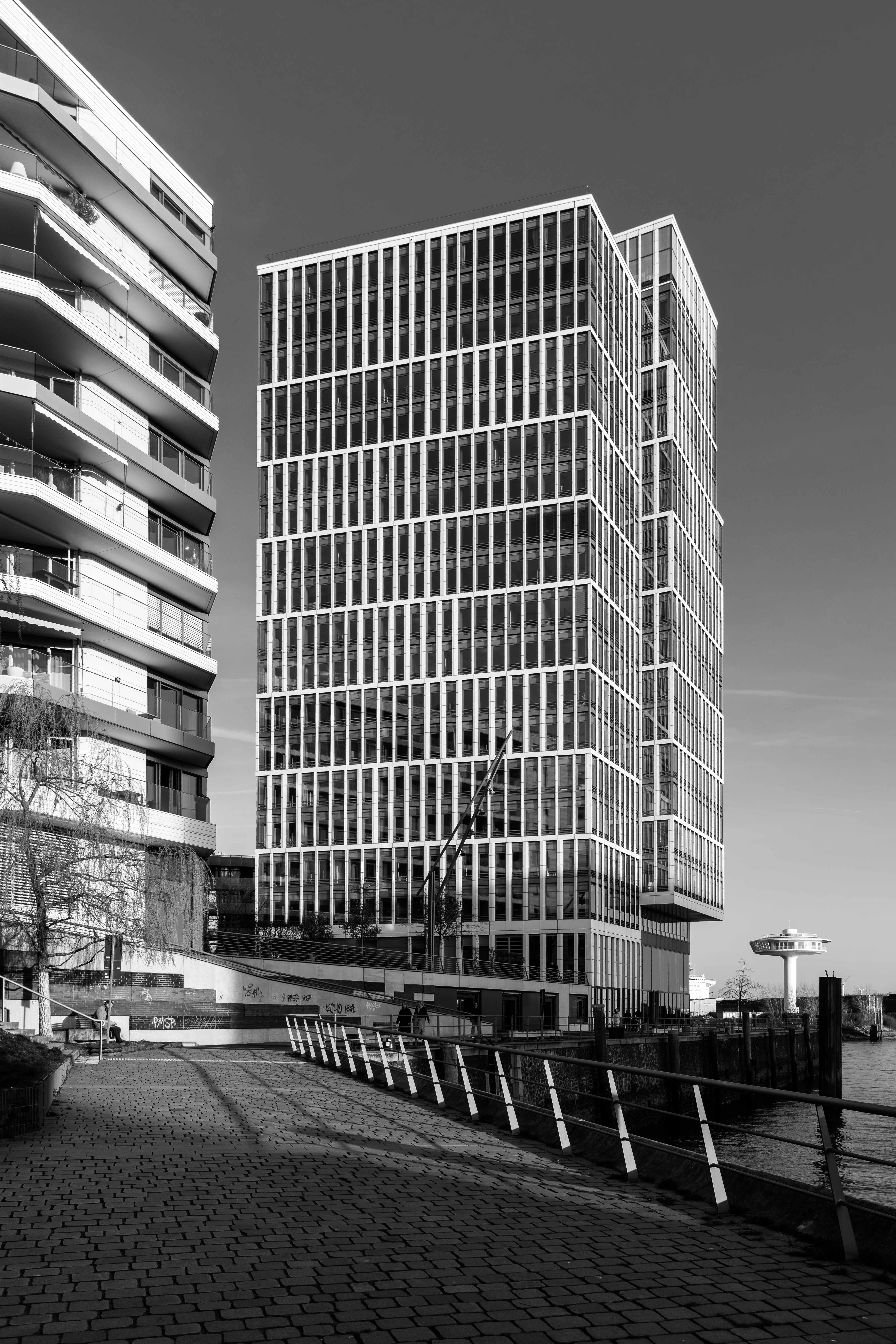 Modern high-rise buildings with vertical lines and shadows in a cityscape.