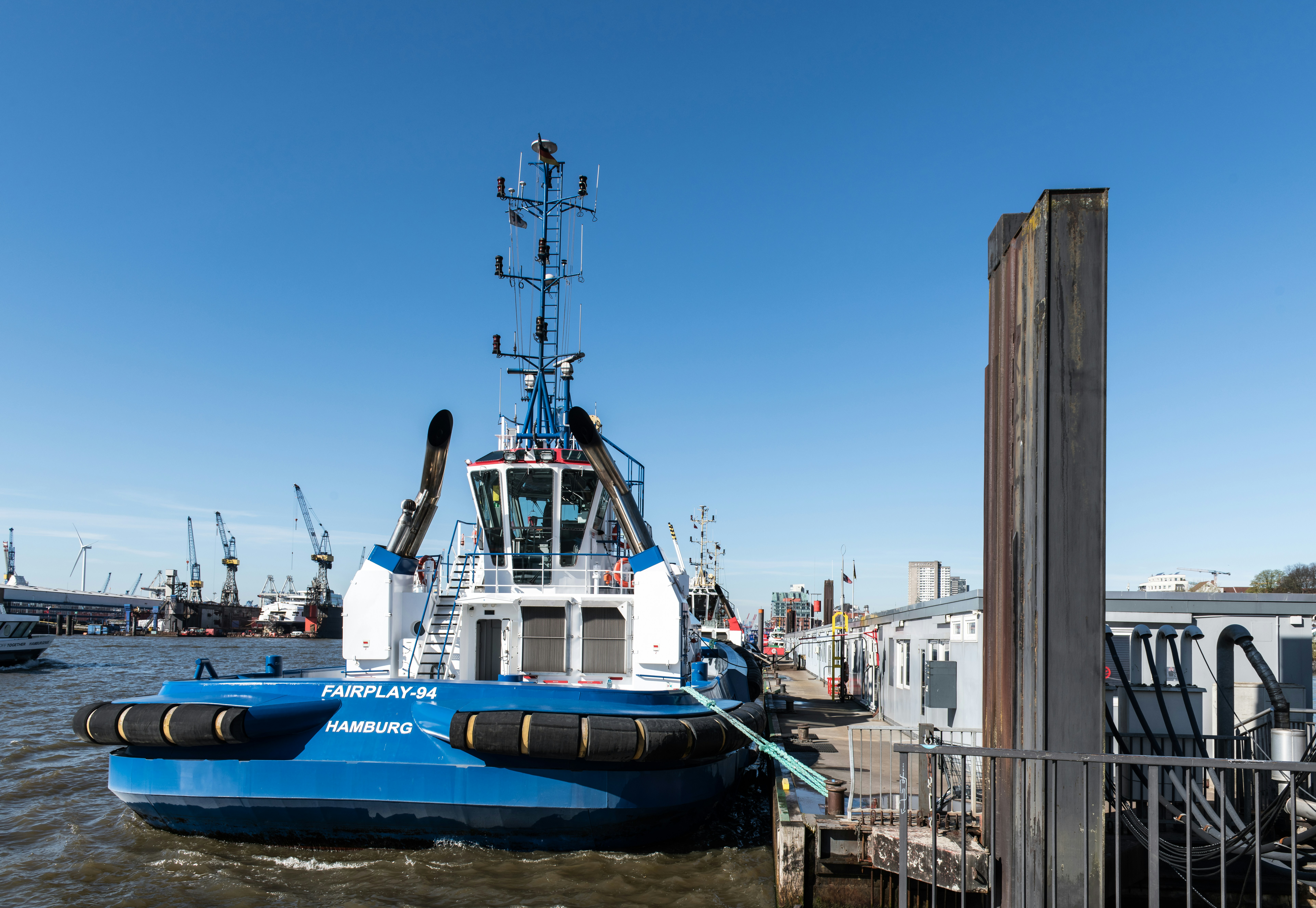 A blue tugboat is docked at a port. photo – Free Human Image on Unsplash