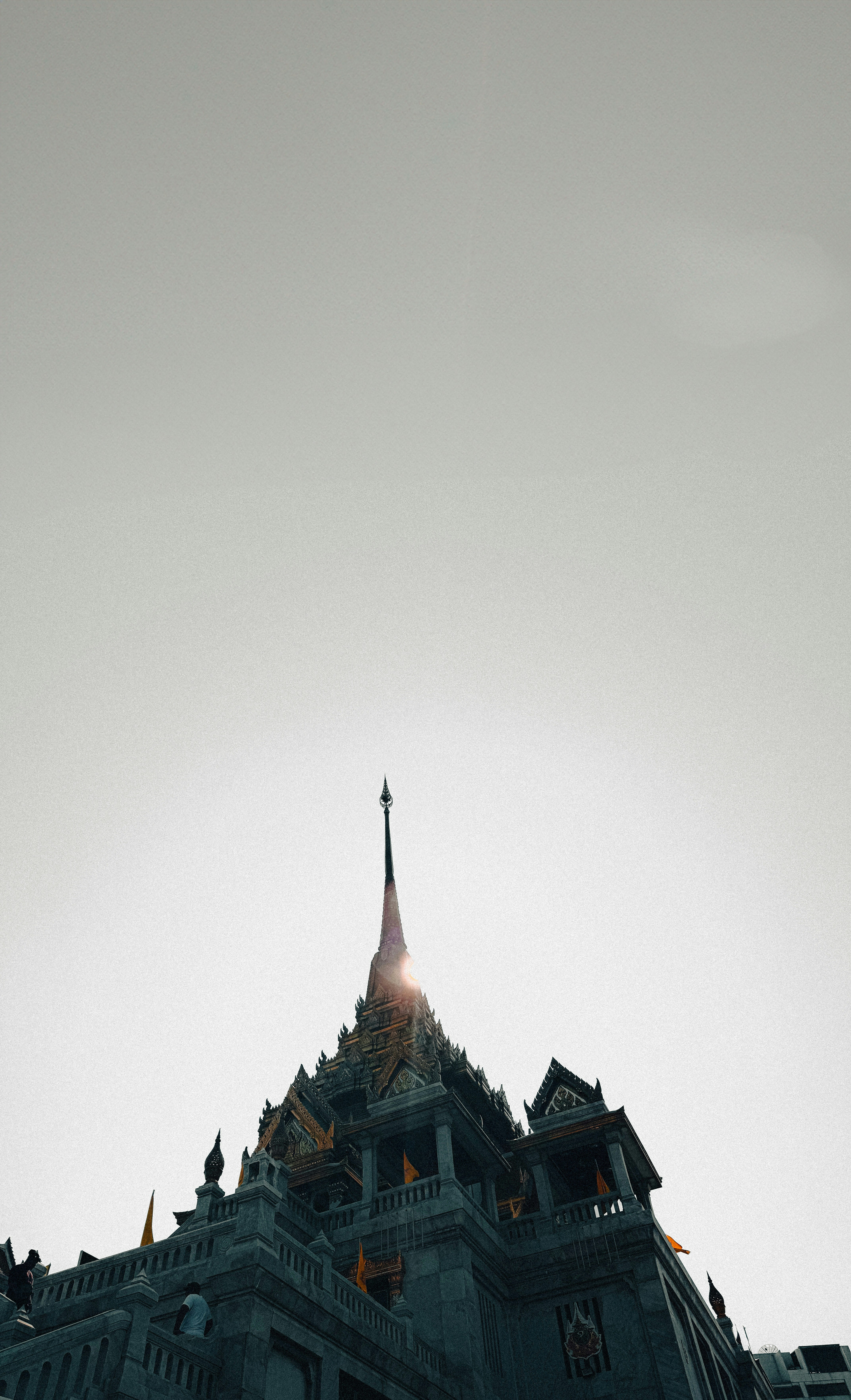 Ornate temple spire reaching into a gradient gray sky, with intricate architectural details visible.