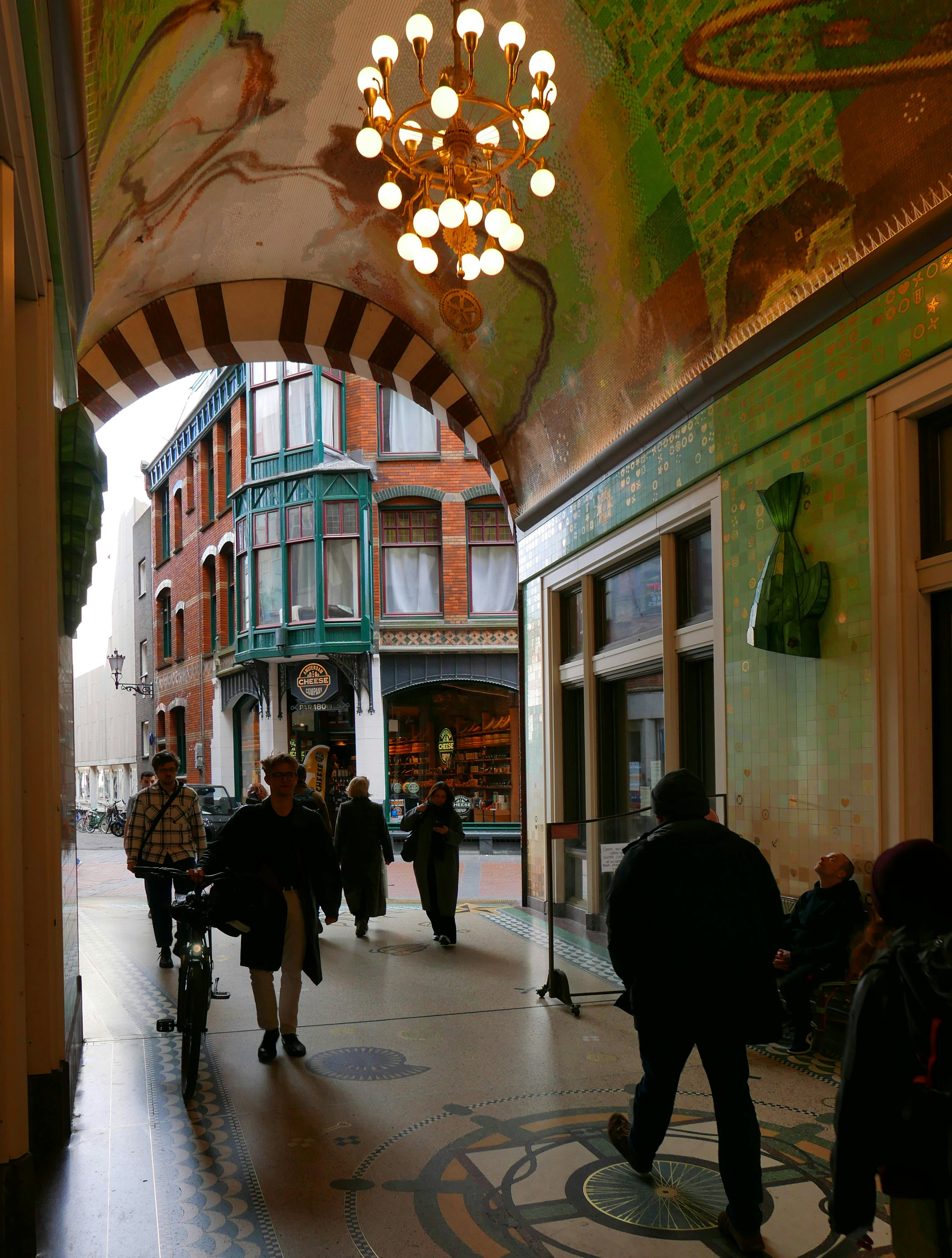 People walking through a decorated passageway with a chandelier in Amsterdam.