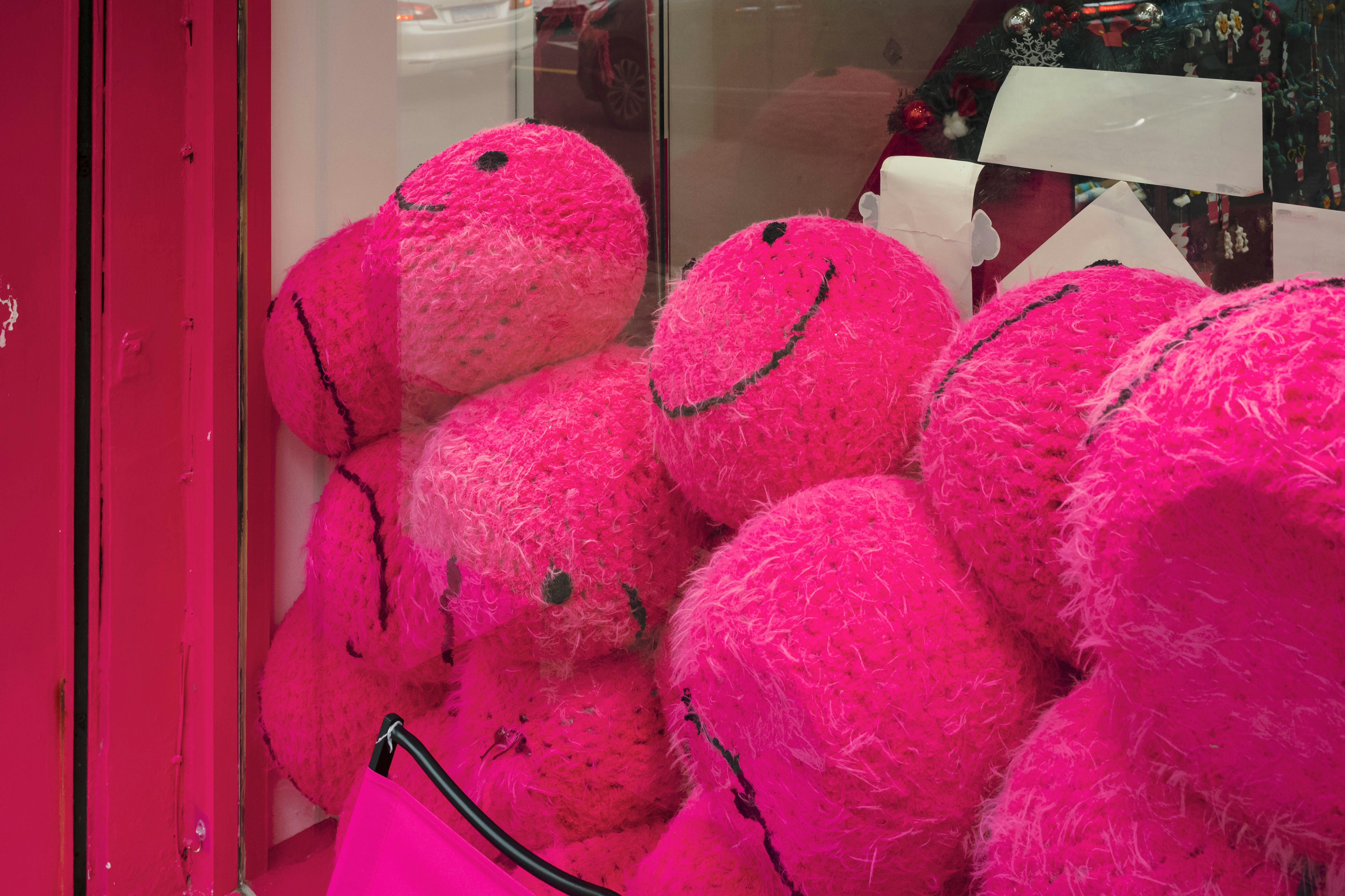 Pink smiling face plushies are inside a display case. photo – Free ...