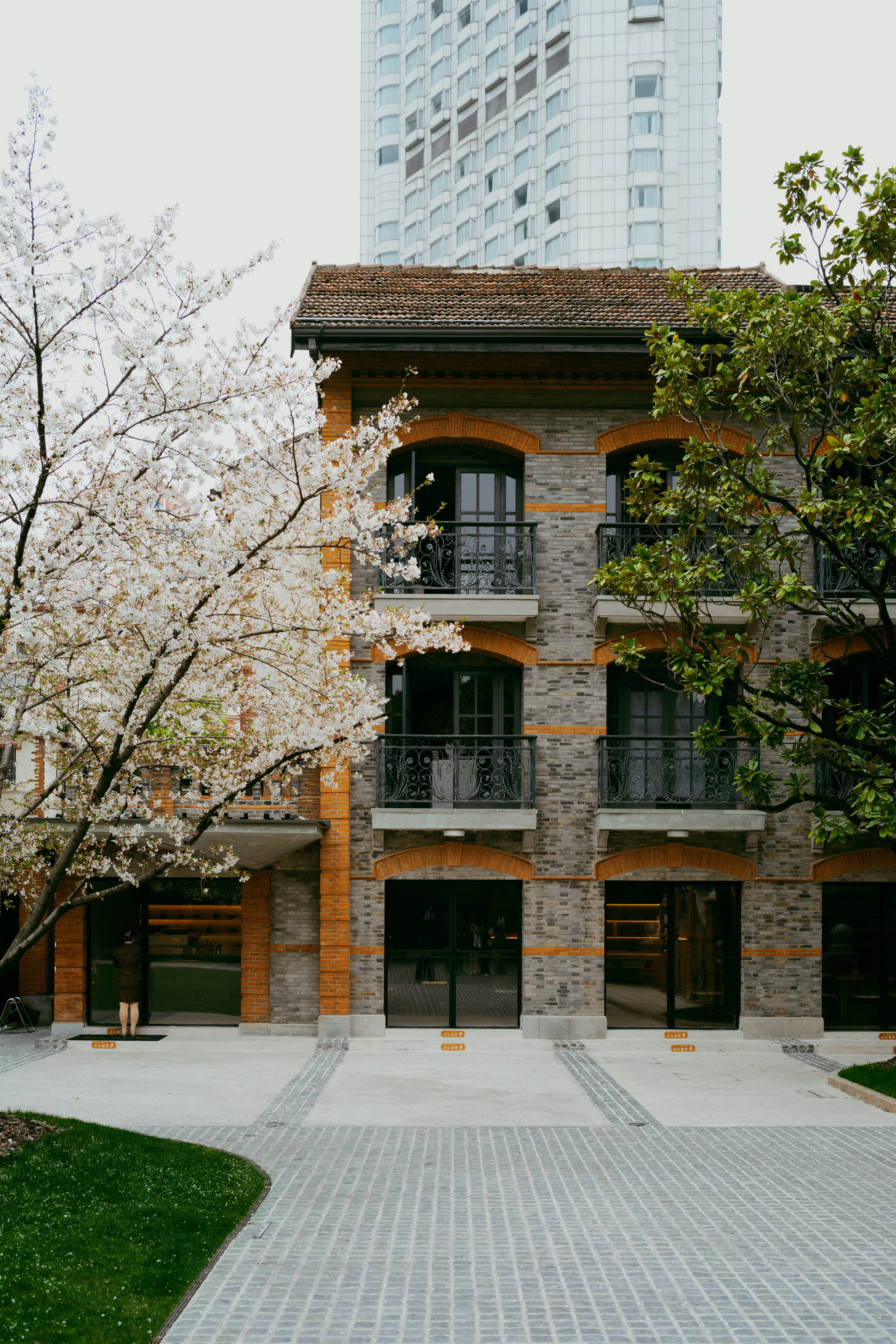 A beautiful brick building surrounded by blooming trees. photo – Free ...