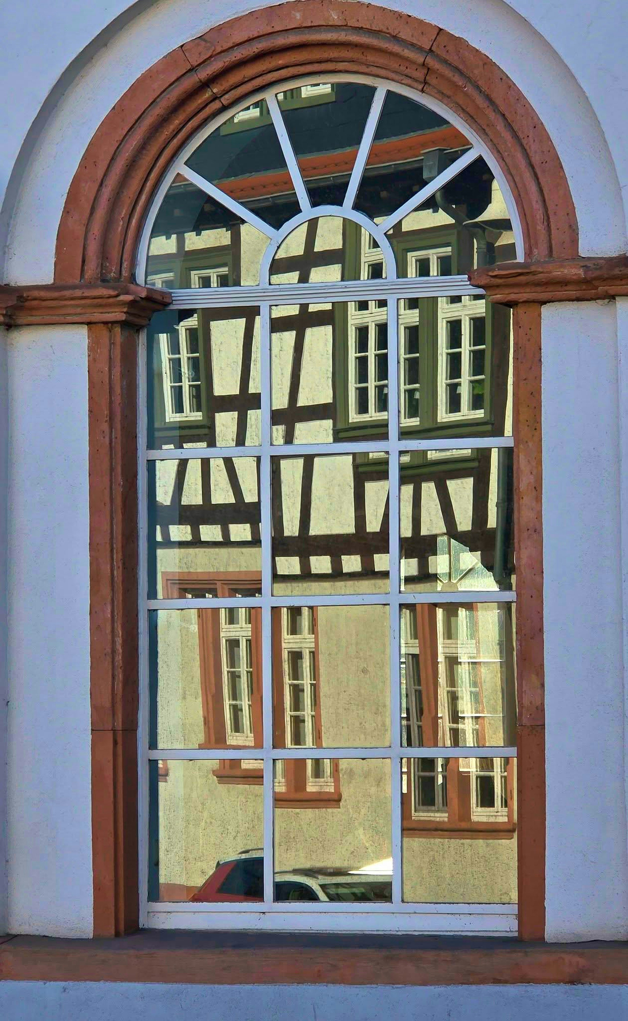Arch Window Reflections: A Half-Timbered Facade Framed in Glass