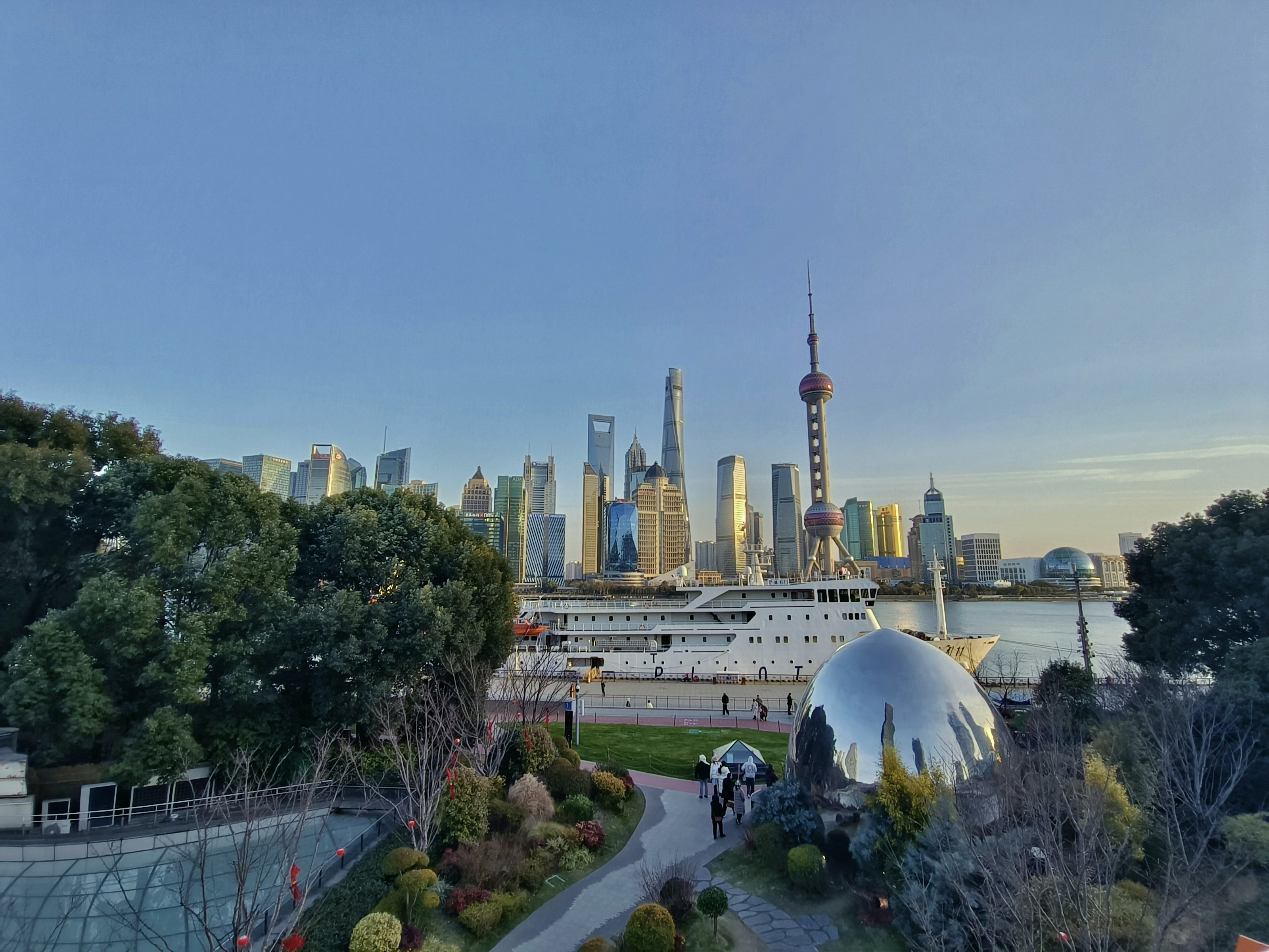 Shanghai skyline with iconic skyscrapers and a reflective dome in the foreground at dusk.