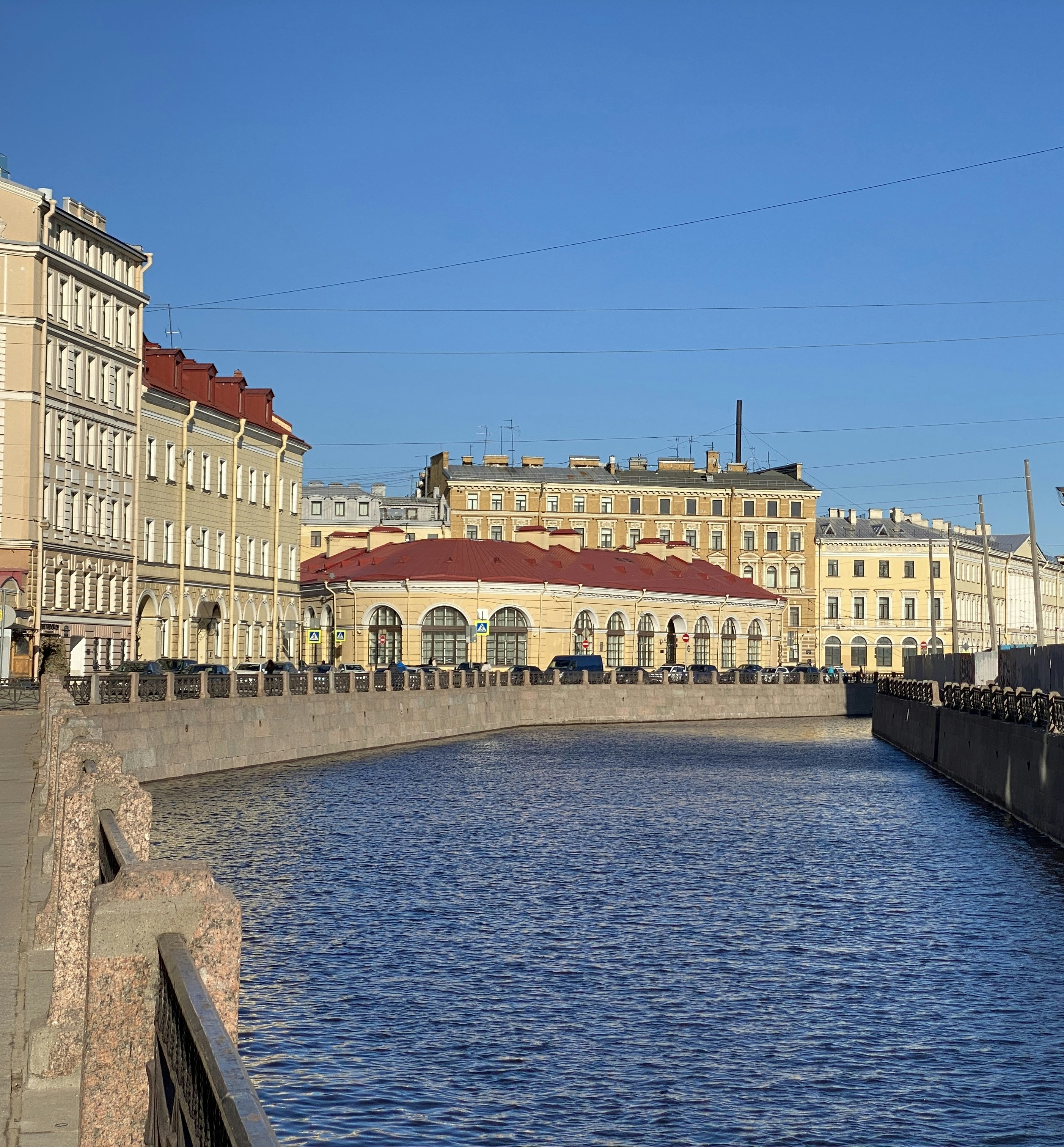 Historic buildings line a sunlit canal under a clear blue sky.