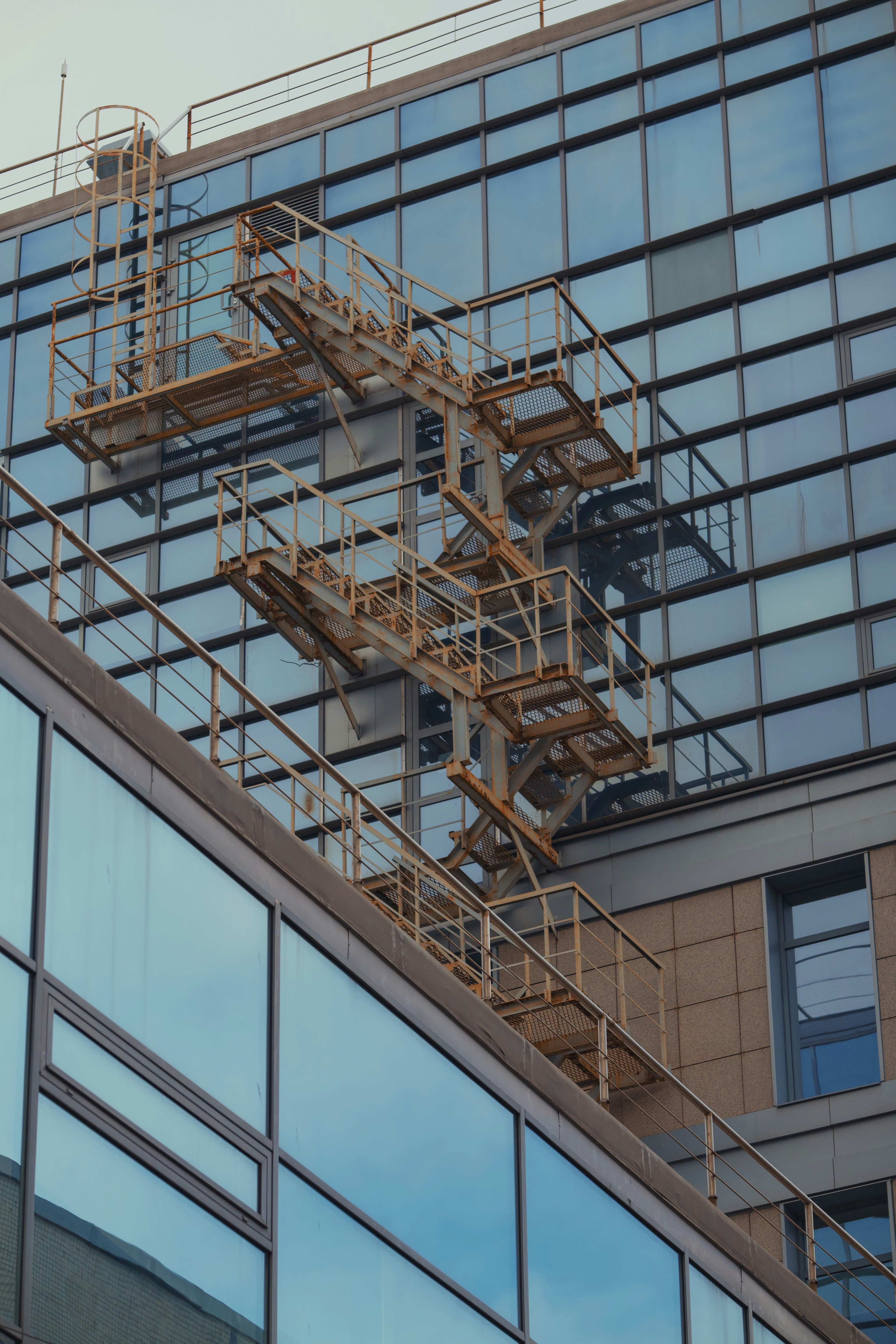 A fire escape clings to a modern glass building. photo – Free Building ...