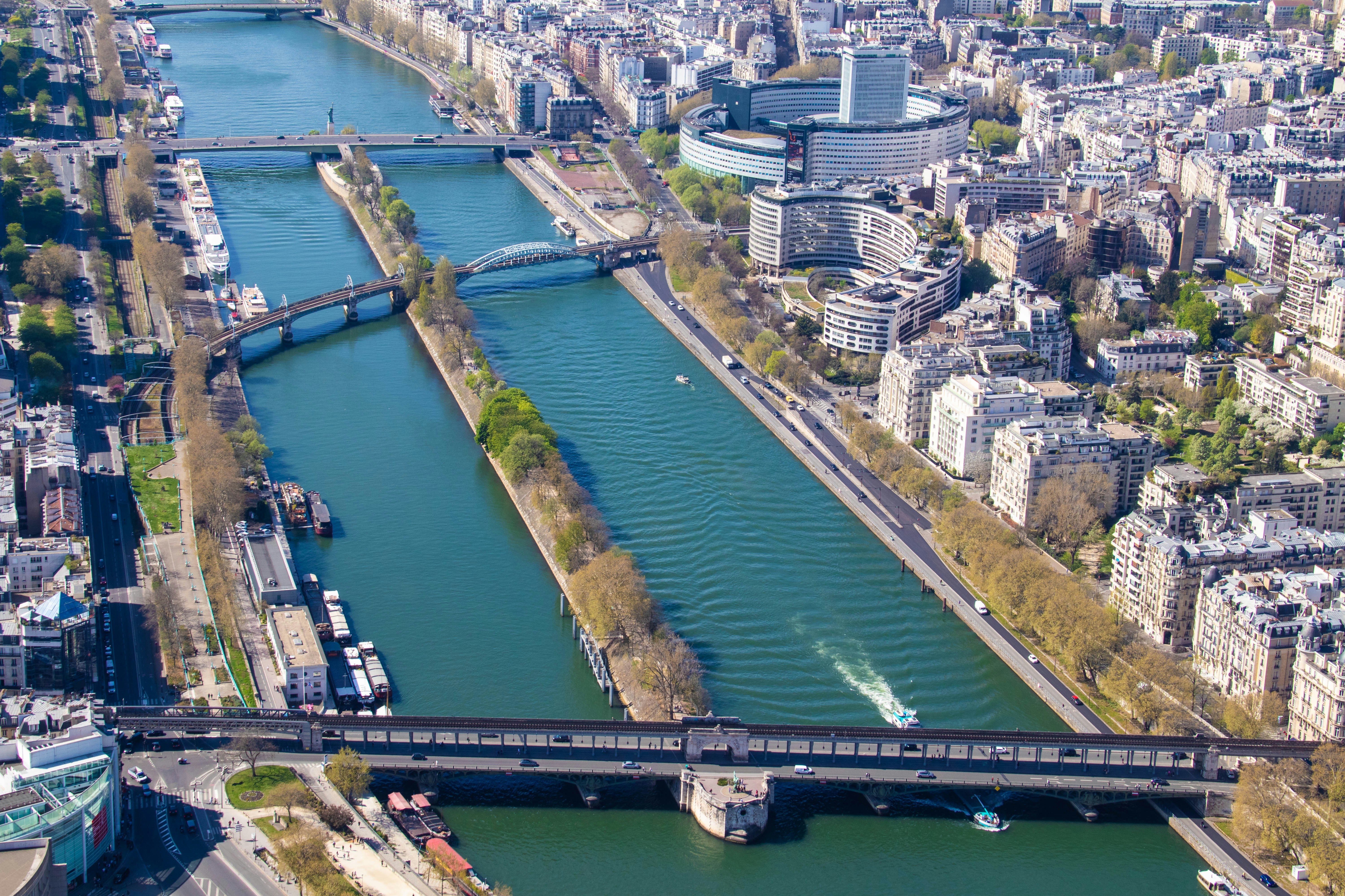 Aerial view of multiple bridges spanning the Seine River in Paris, lined with urban architecture and green spaces.