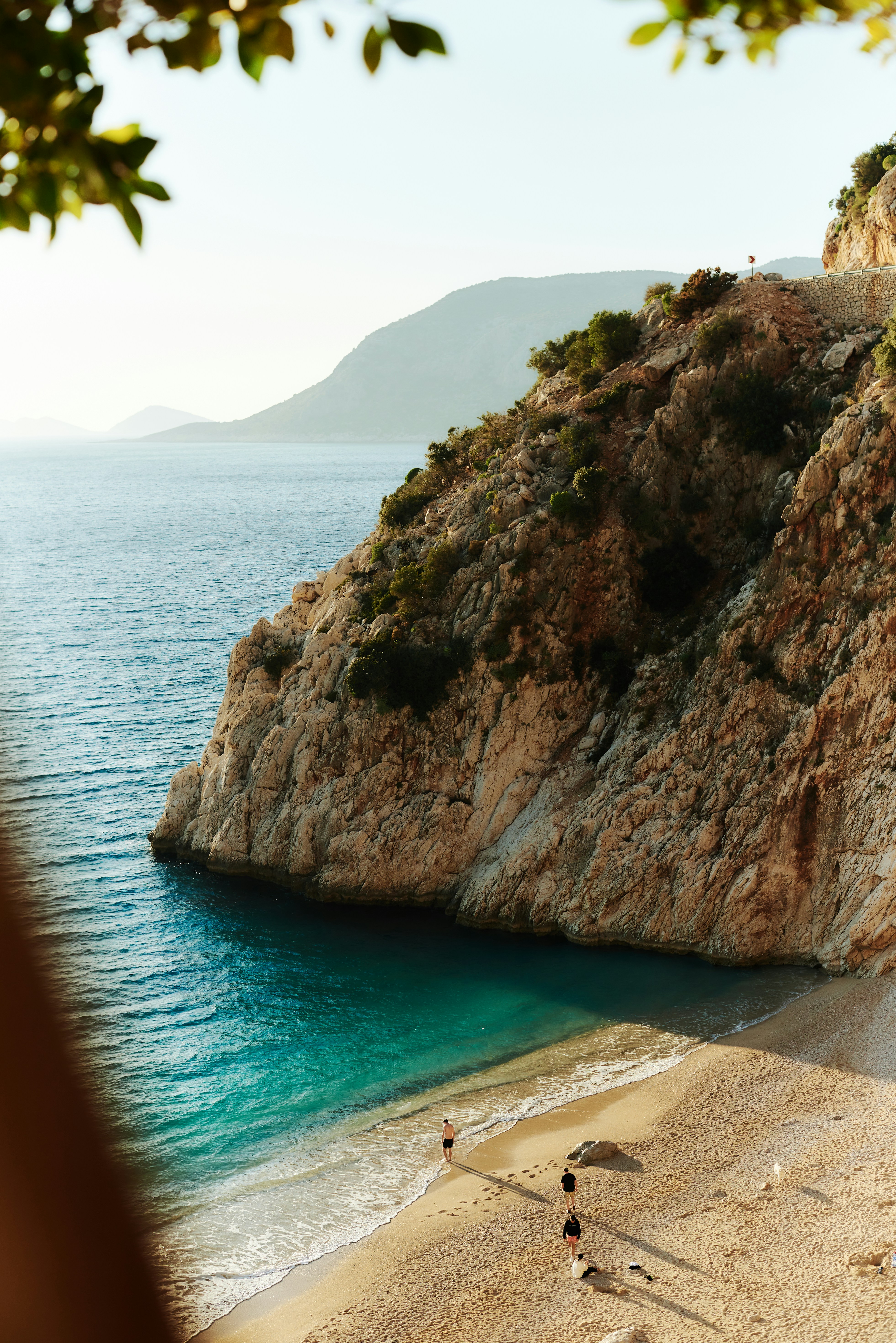 Golden cliffs meet turquoise waters on a serene Mediterranean beach.