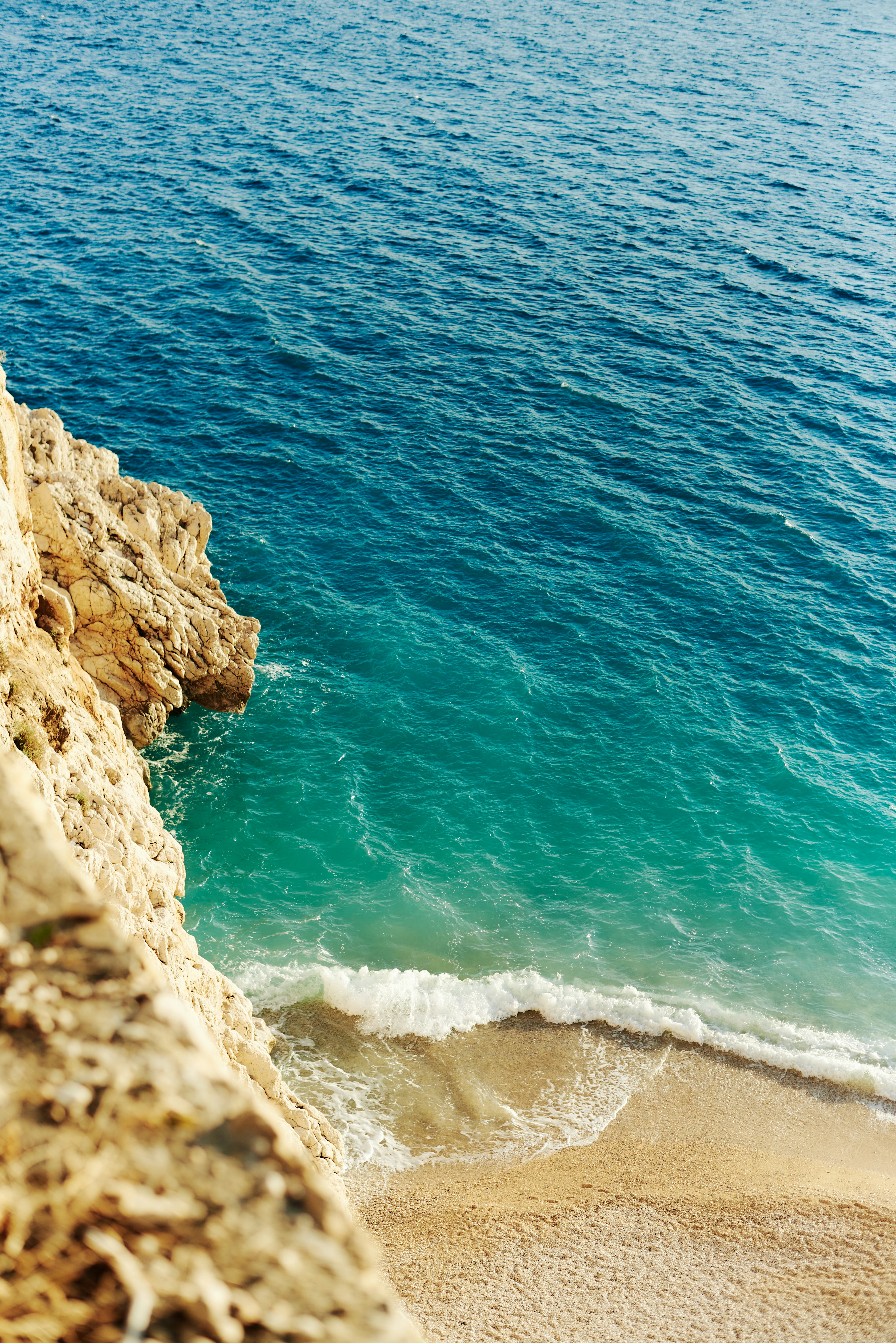 Cliffside view of a secluded beach with turquoise waters meeting golden sand.