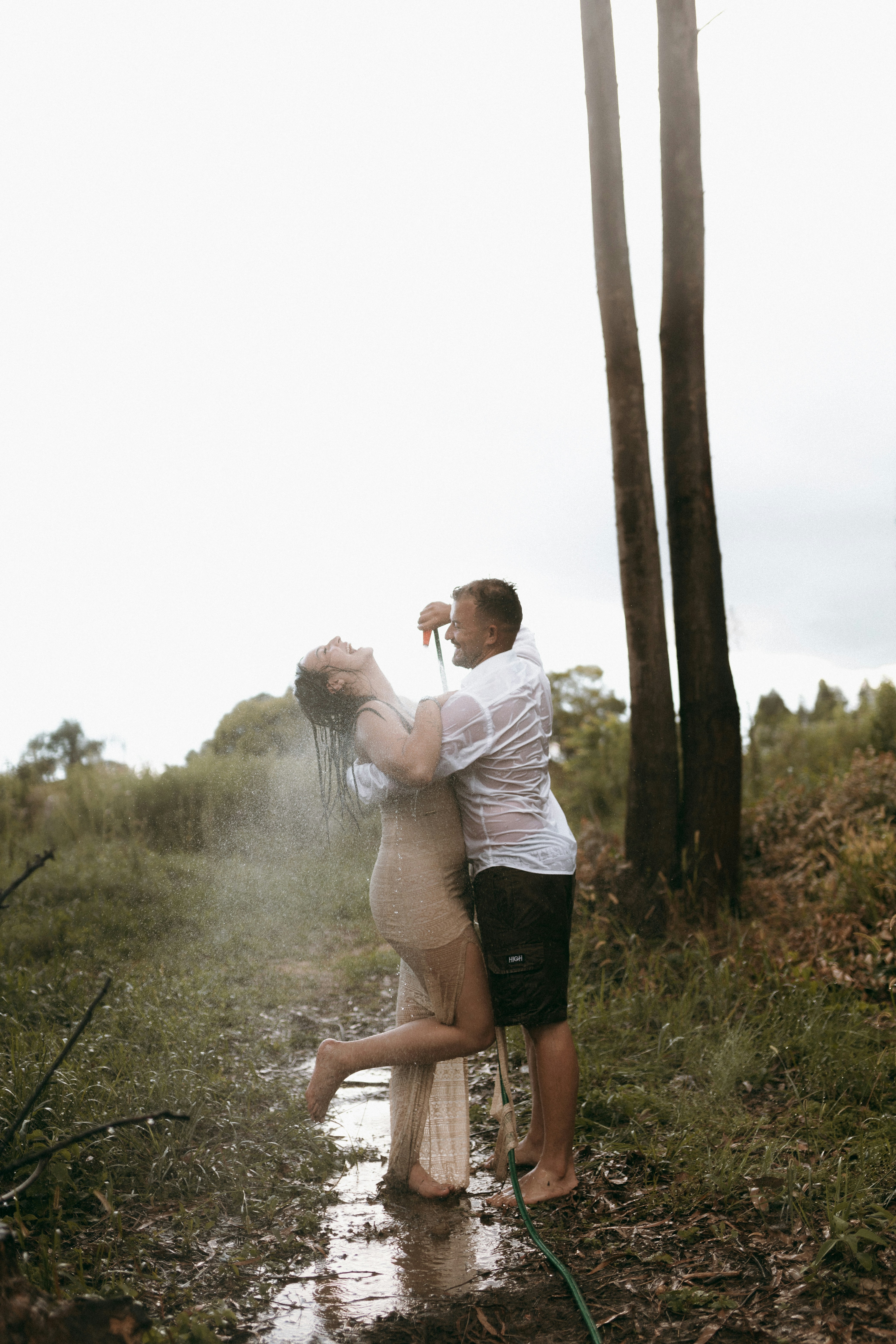 Drenched Promise: A Kiss and Laugh Amid Rain on a Rural Trail