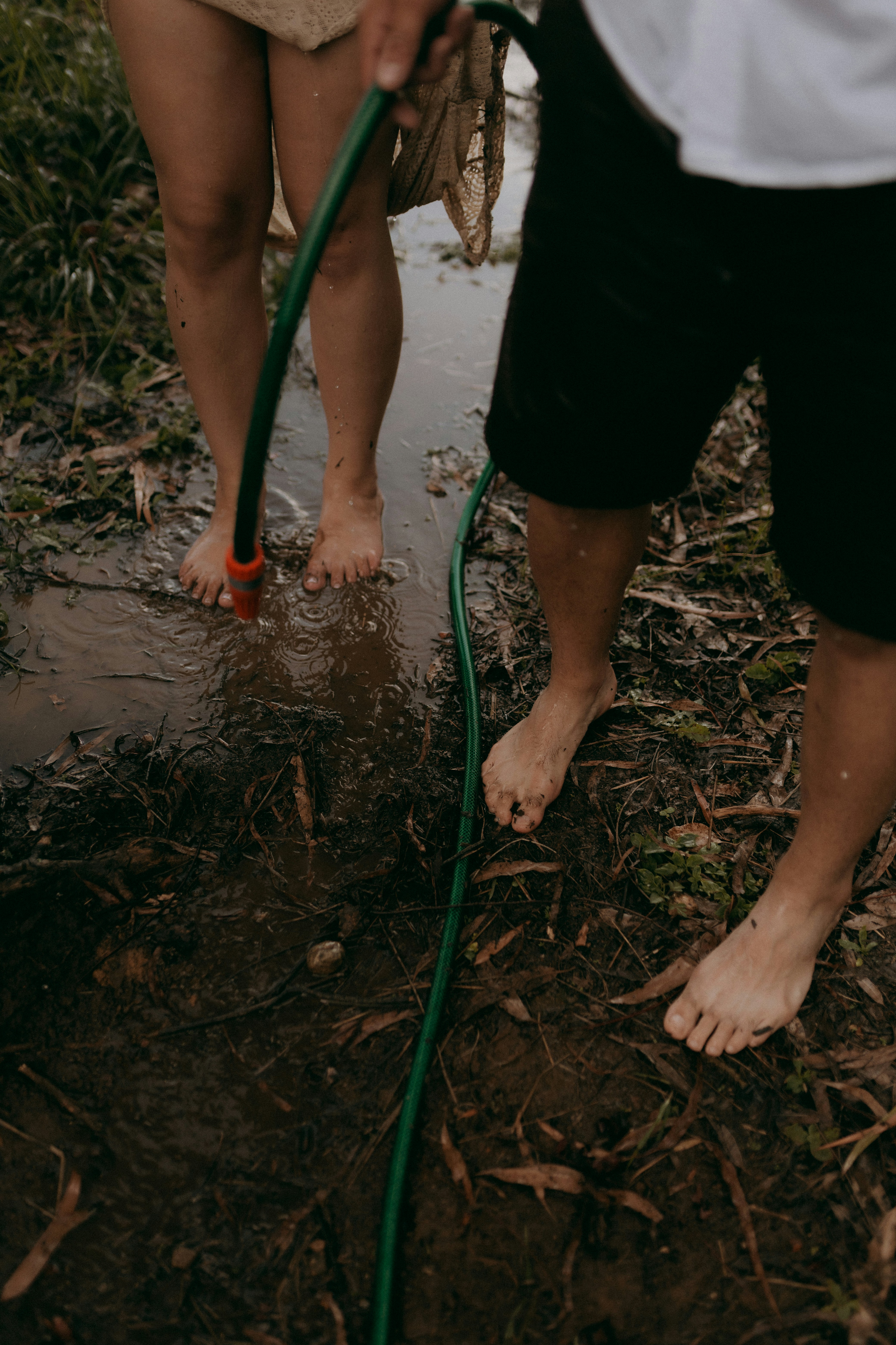 People are cleaning muddy feet with a hose. photo – Free Human Image on ...