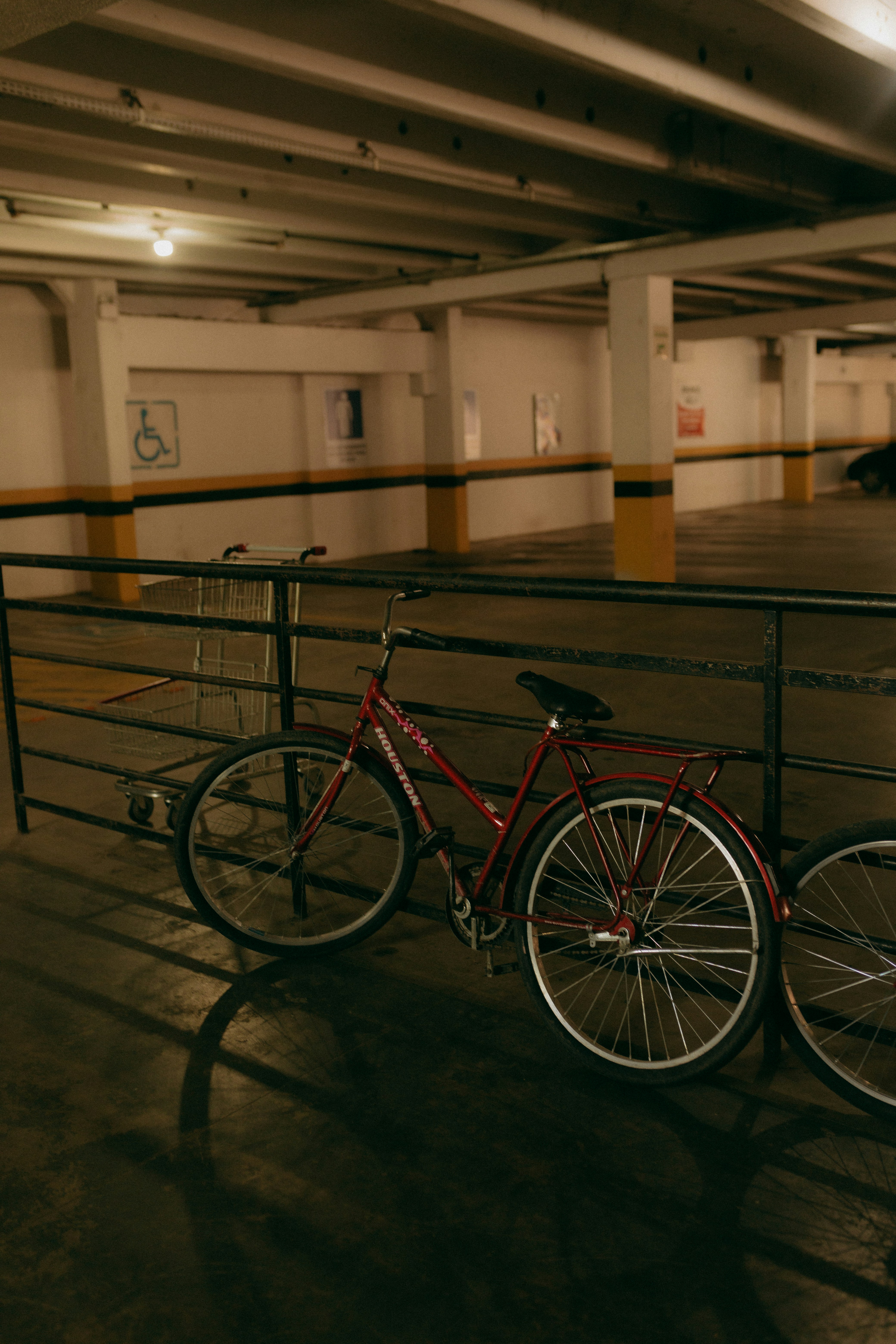 A red bicycle is parked in a parking garage. photo – Free Car Image on ...