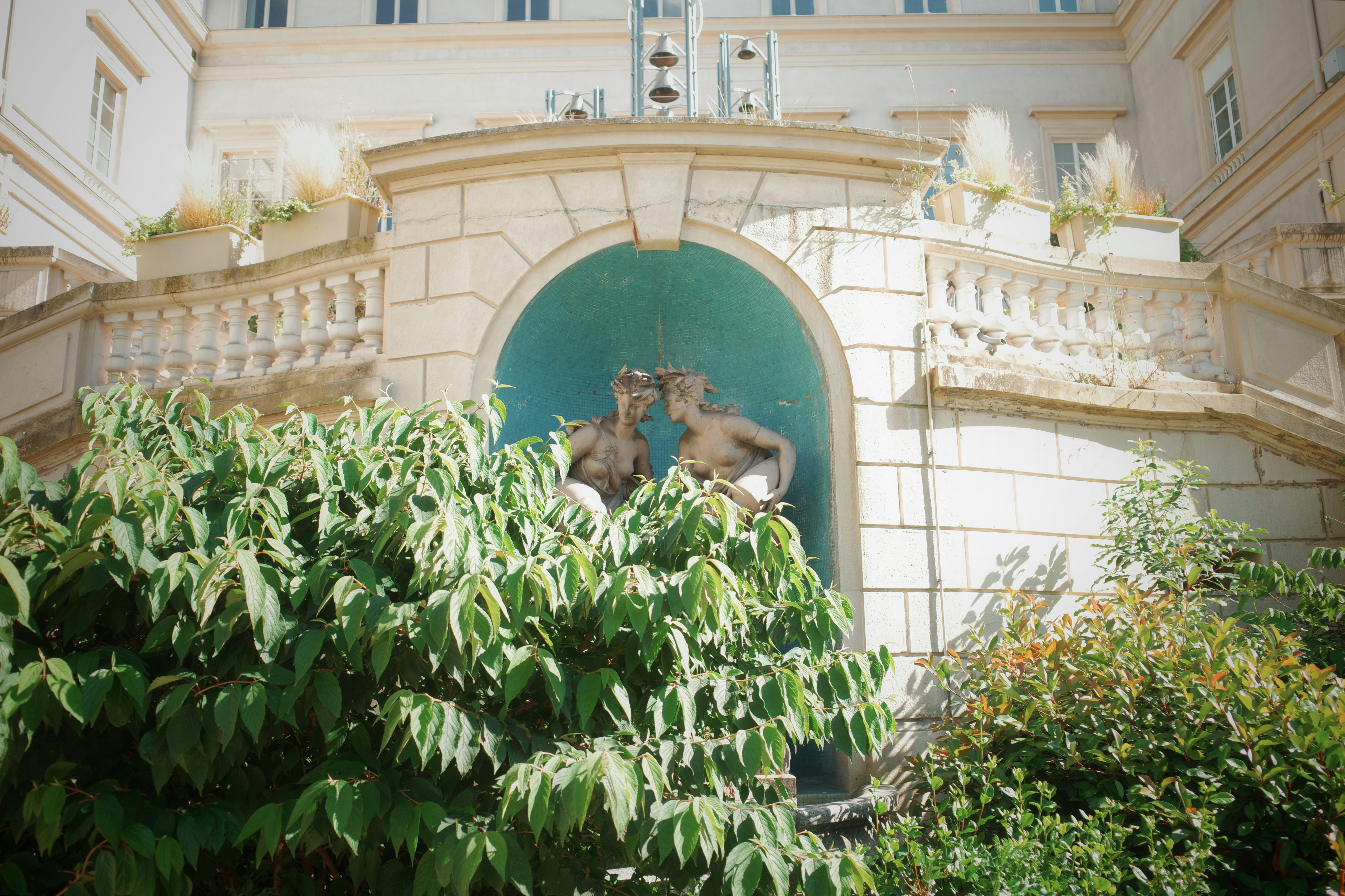 Statue in a Turquoise Niche Framed by Verdant Courtyard