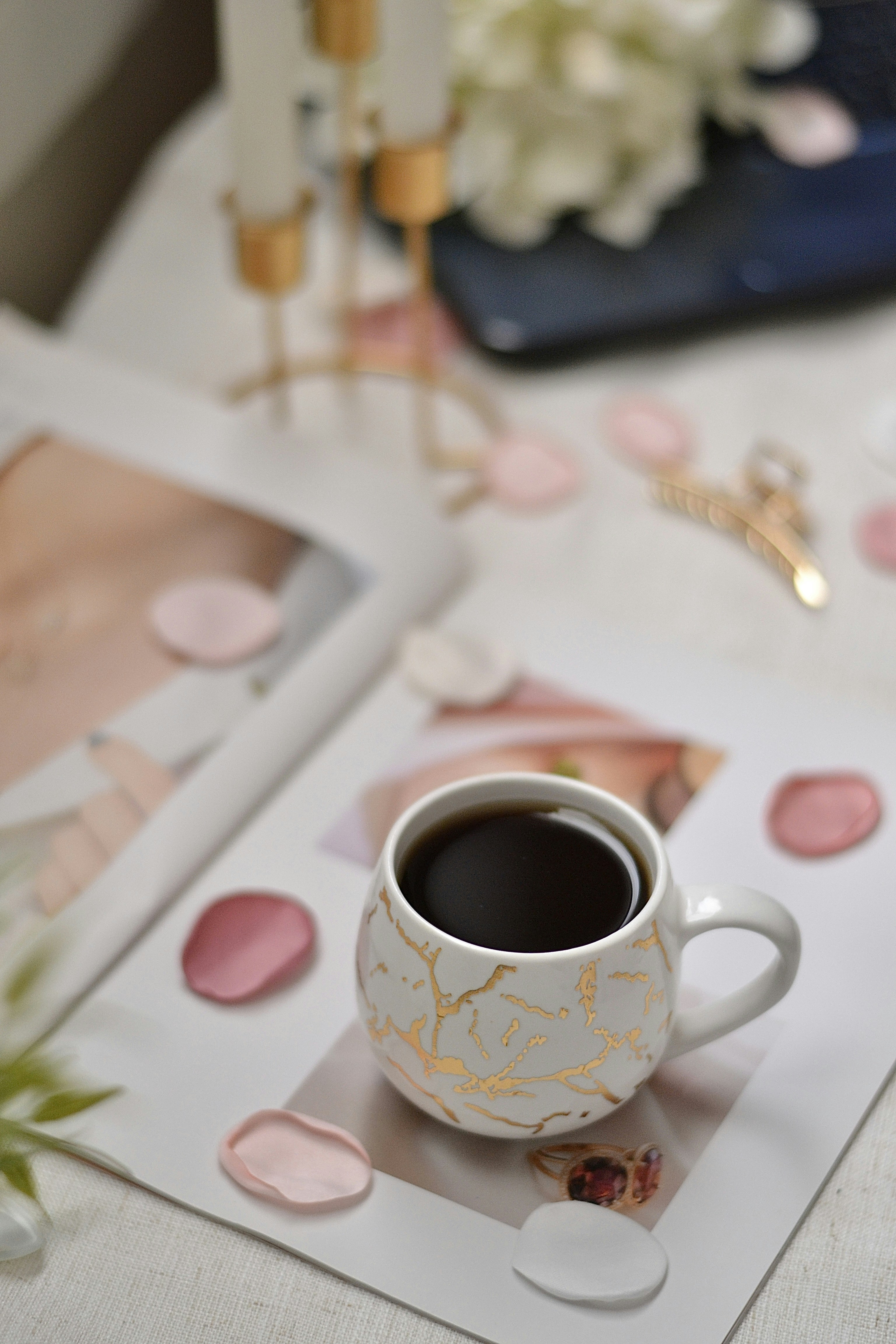 Coffee cup, magazine, candles, and petals.