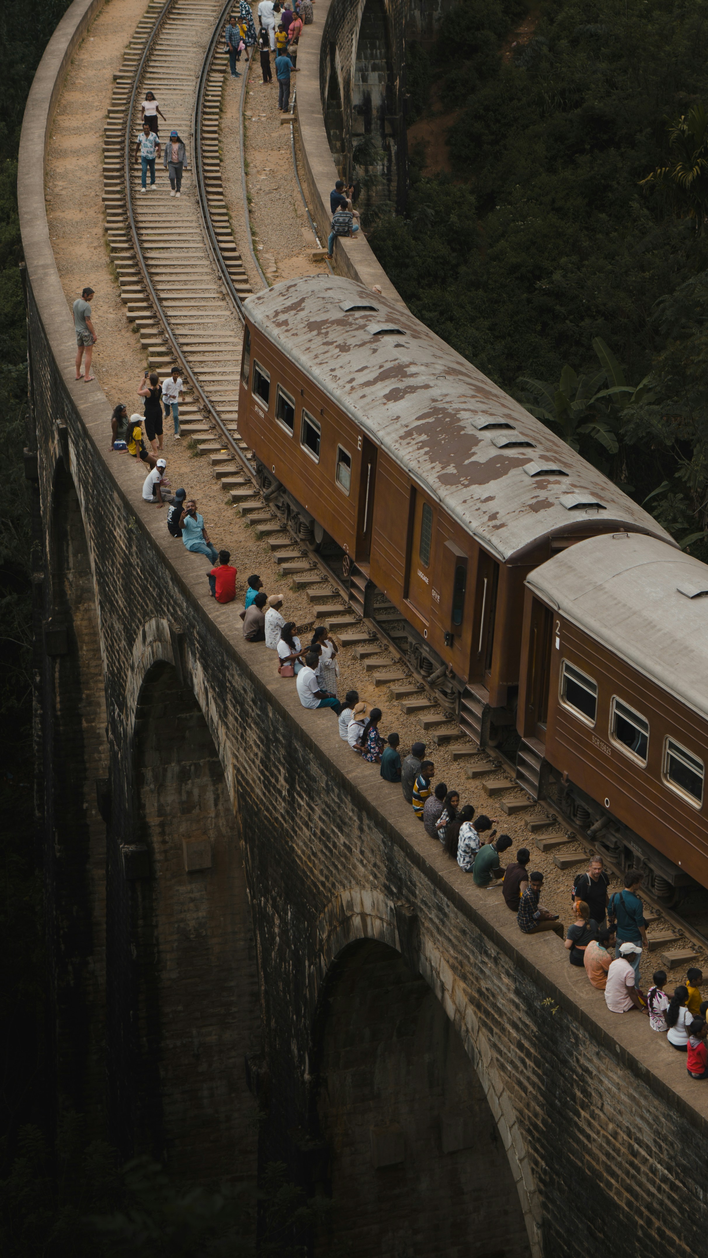 Train traveling on a bridge with people sitting on it. photo – Free ...