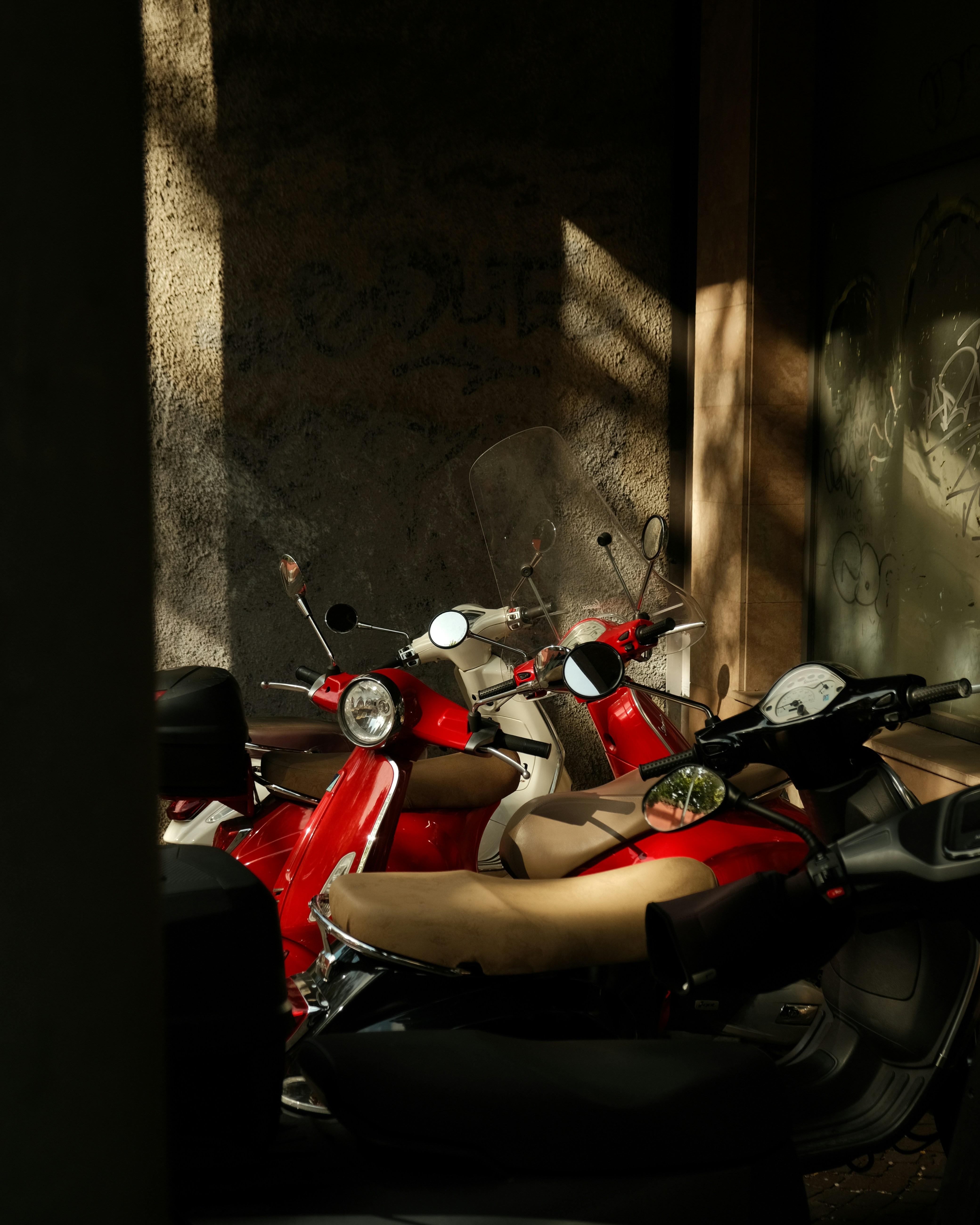 Sunlit Cluster: Red Scooters Resting in a Narrow Alley