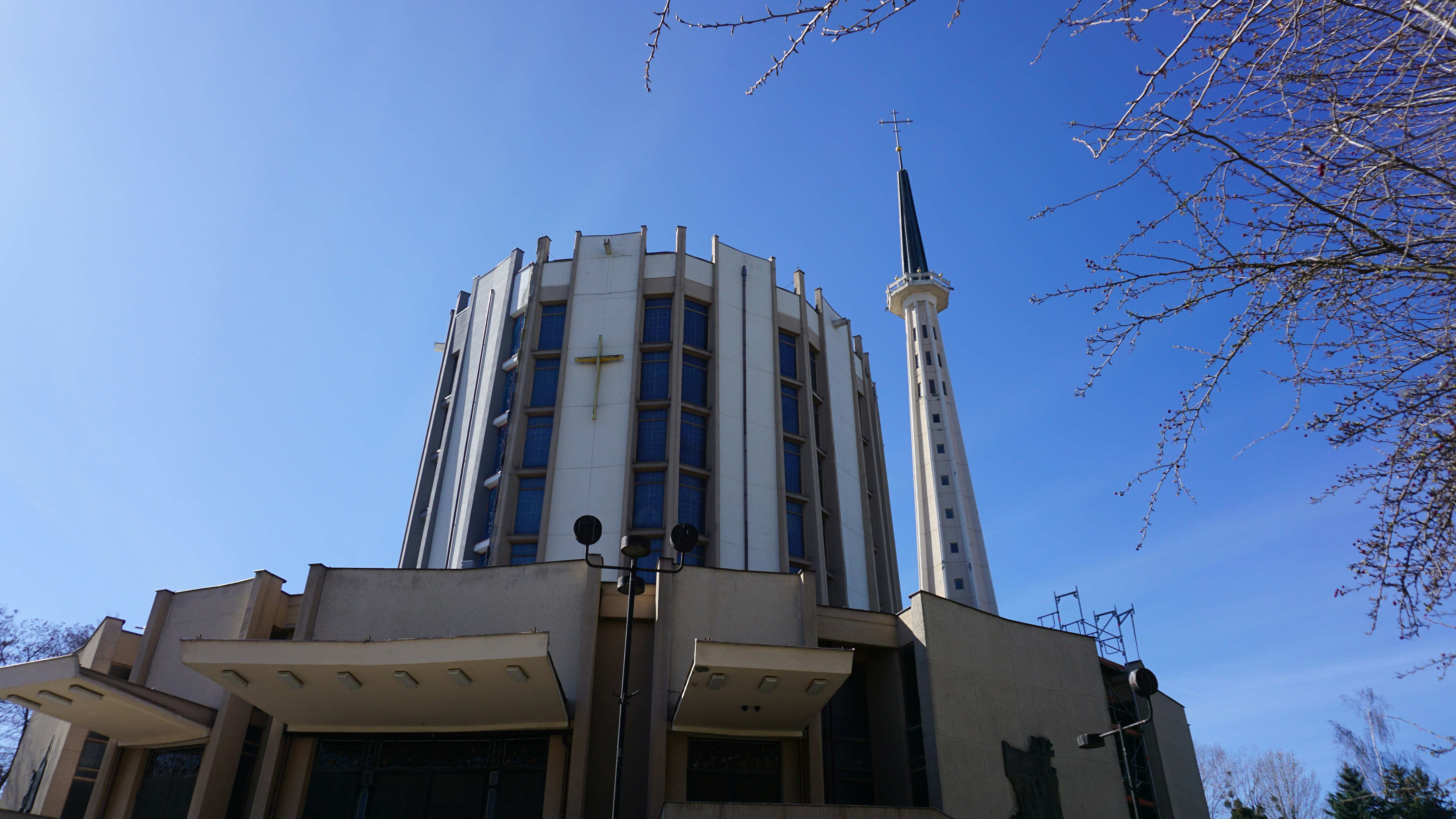 Concrete Cathedral: A Circular-Facade Church with a Slender Spire Against a Bright Blue Sky