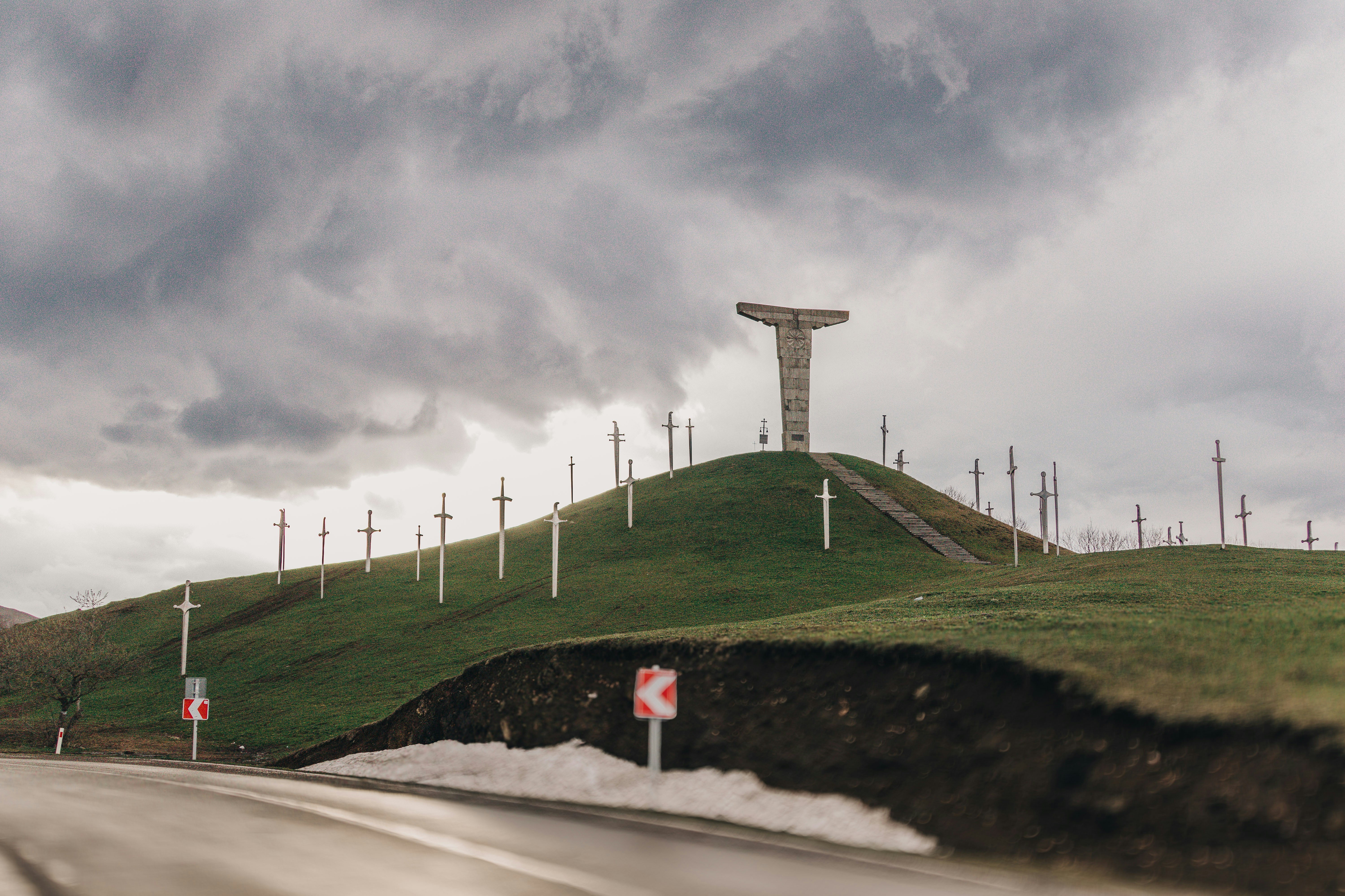 Swords monument on a grassy hill under a cloudy sky. photo – Free ...