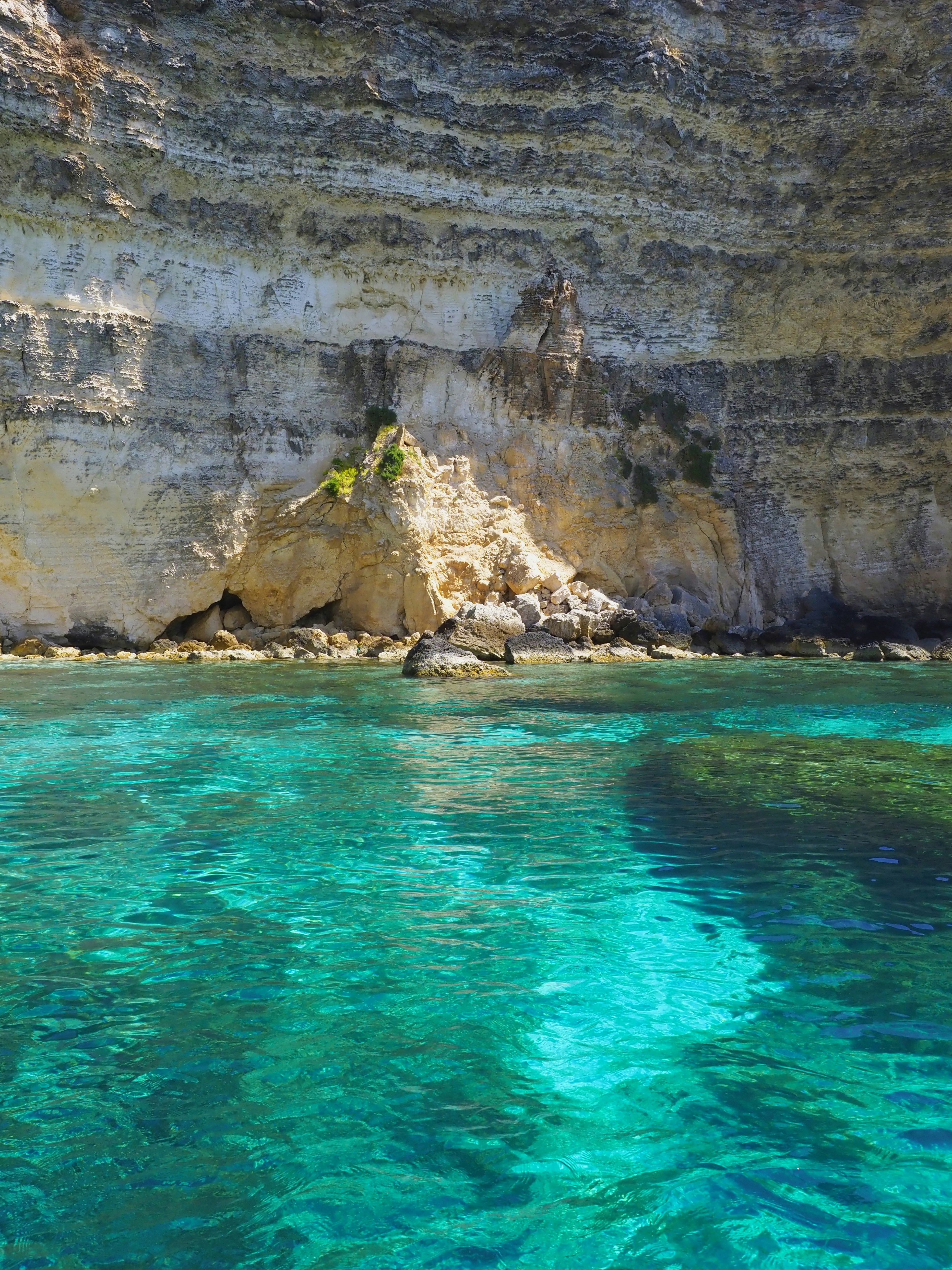 Turquoise water shimmering below a towering limestone cliff.