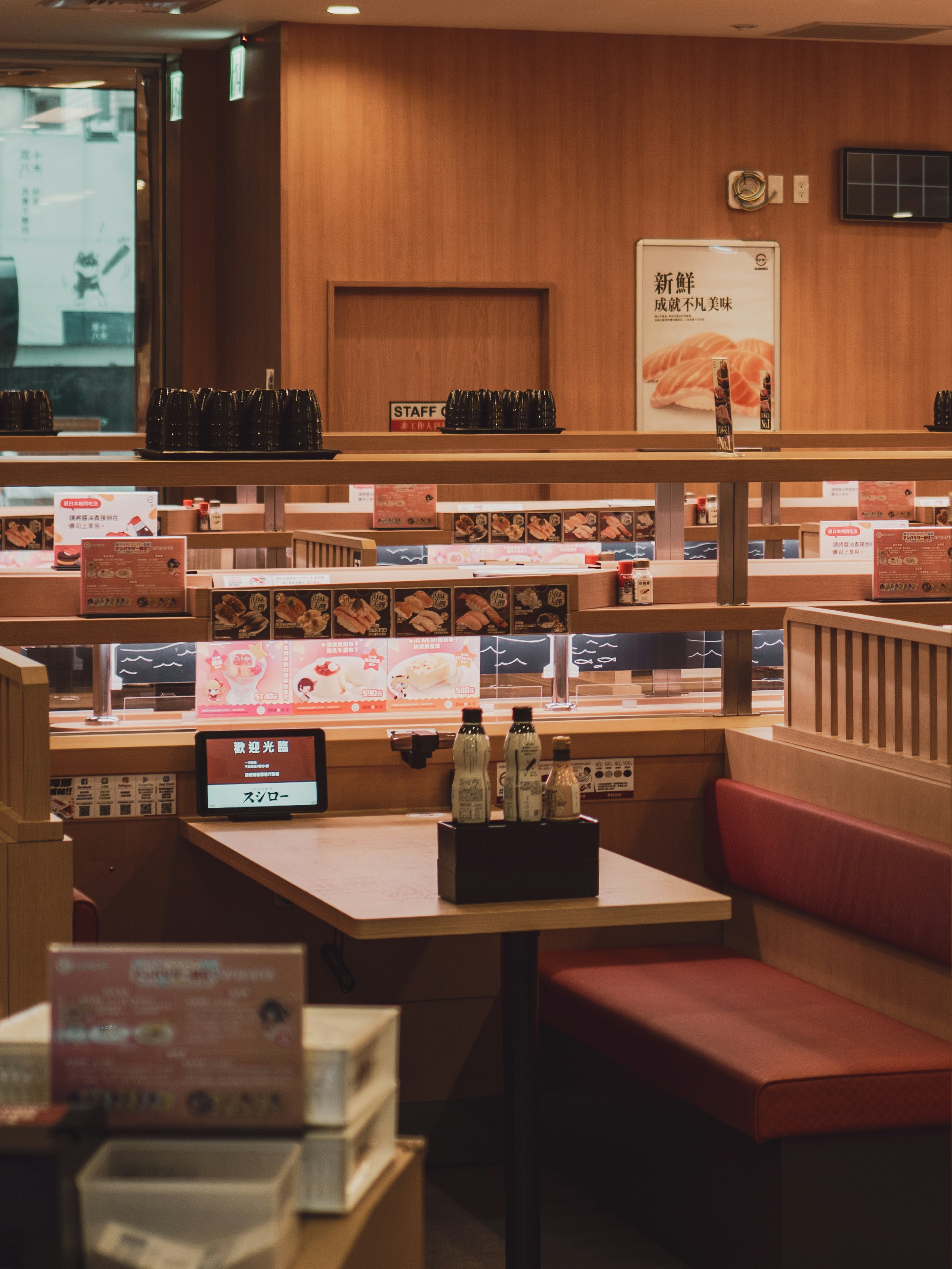 Empty sushi restaurant with wooden decor and neatly arranged tables during a quiet afternoon.
