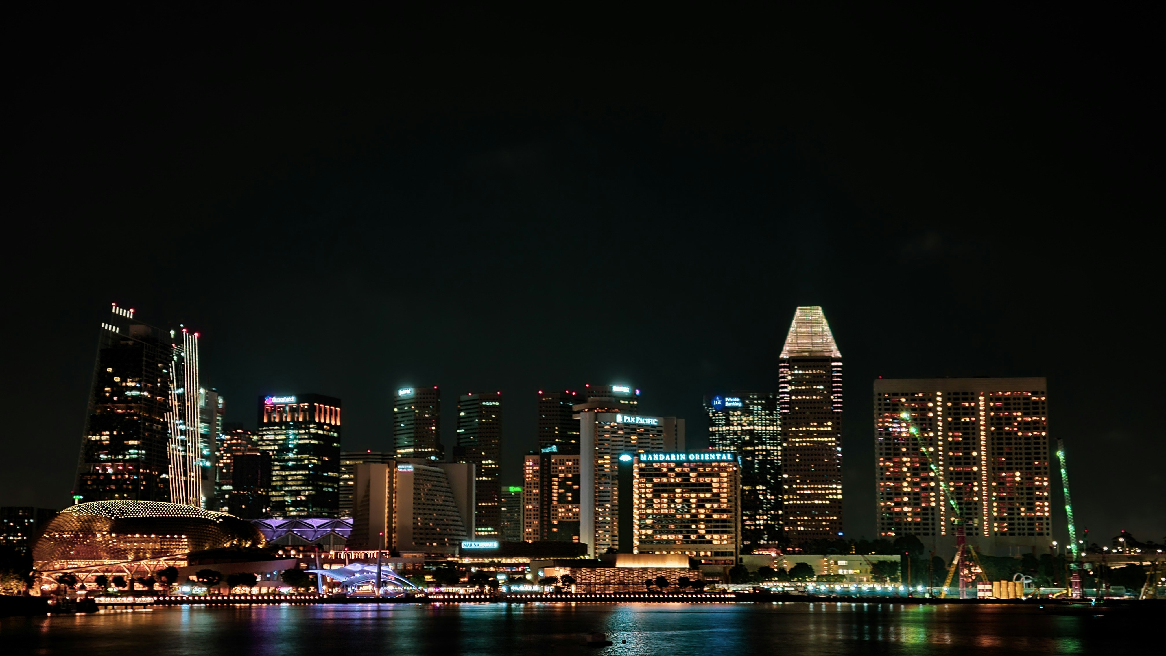 City skyline at night with vibrant lights reflecting on the water.