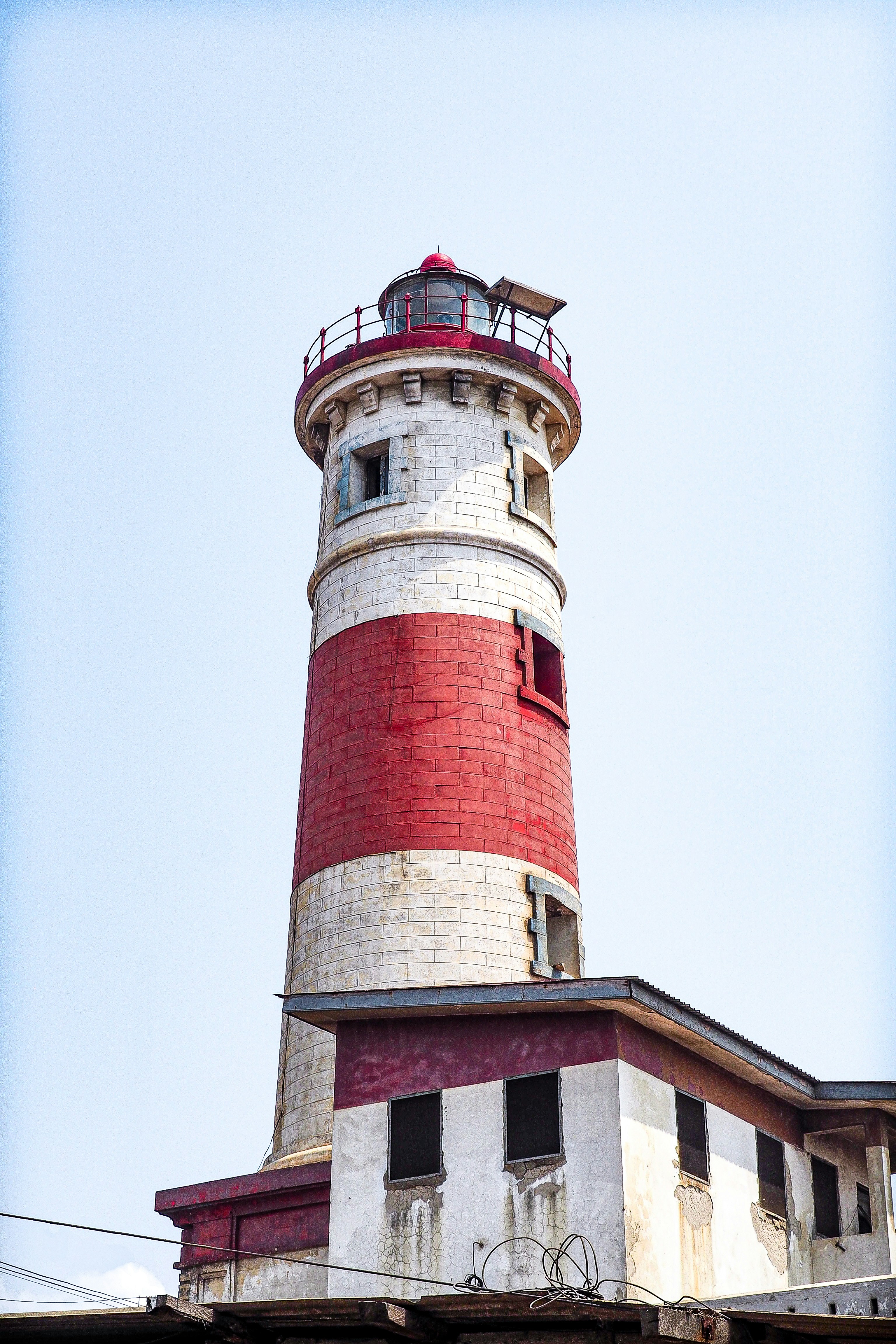 Red and white lighthouse standing tall against a clear blue sky.