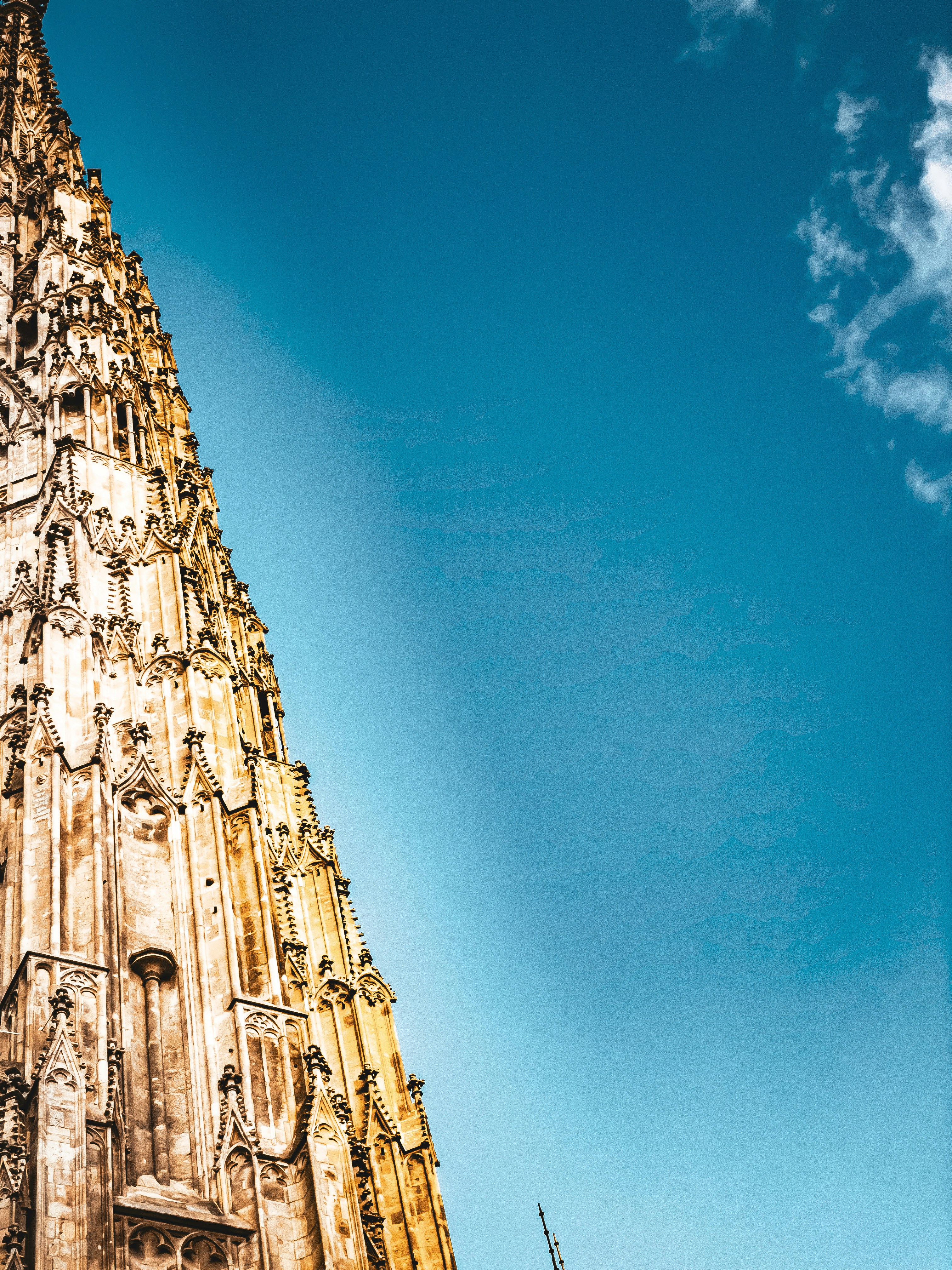 Intricate spire of a historic cathedral reaching towards a clear blue sky.