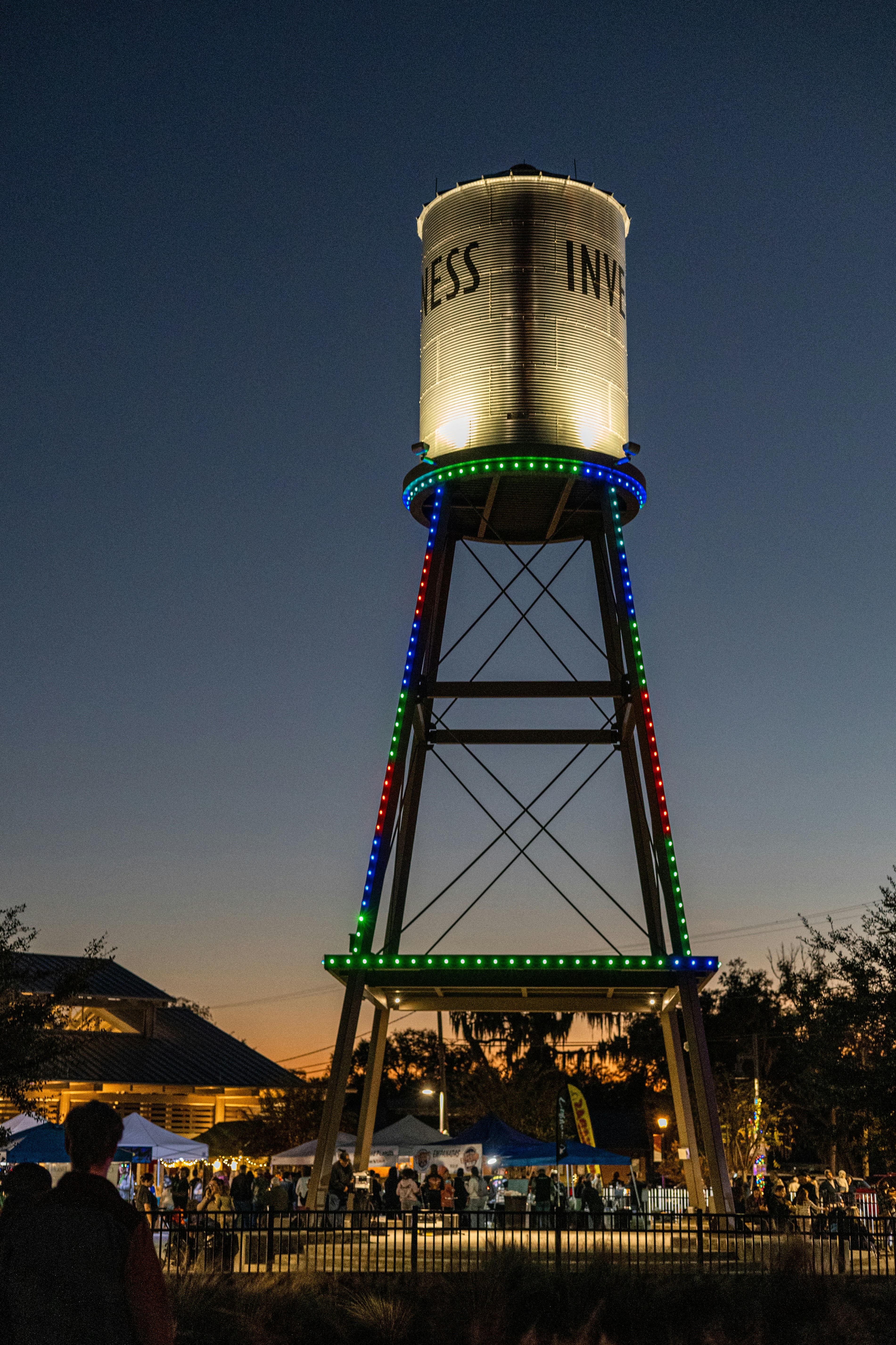 Twilight Neon: The Water Tower Wreathed in Multicolor Light Over a Night Market