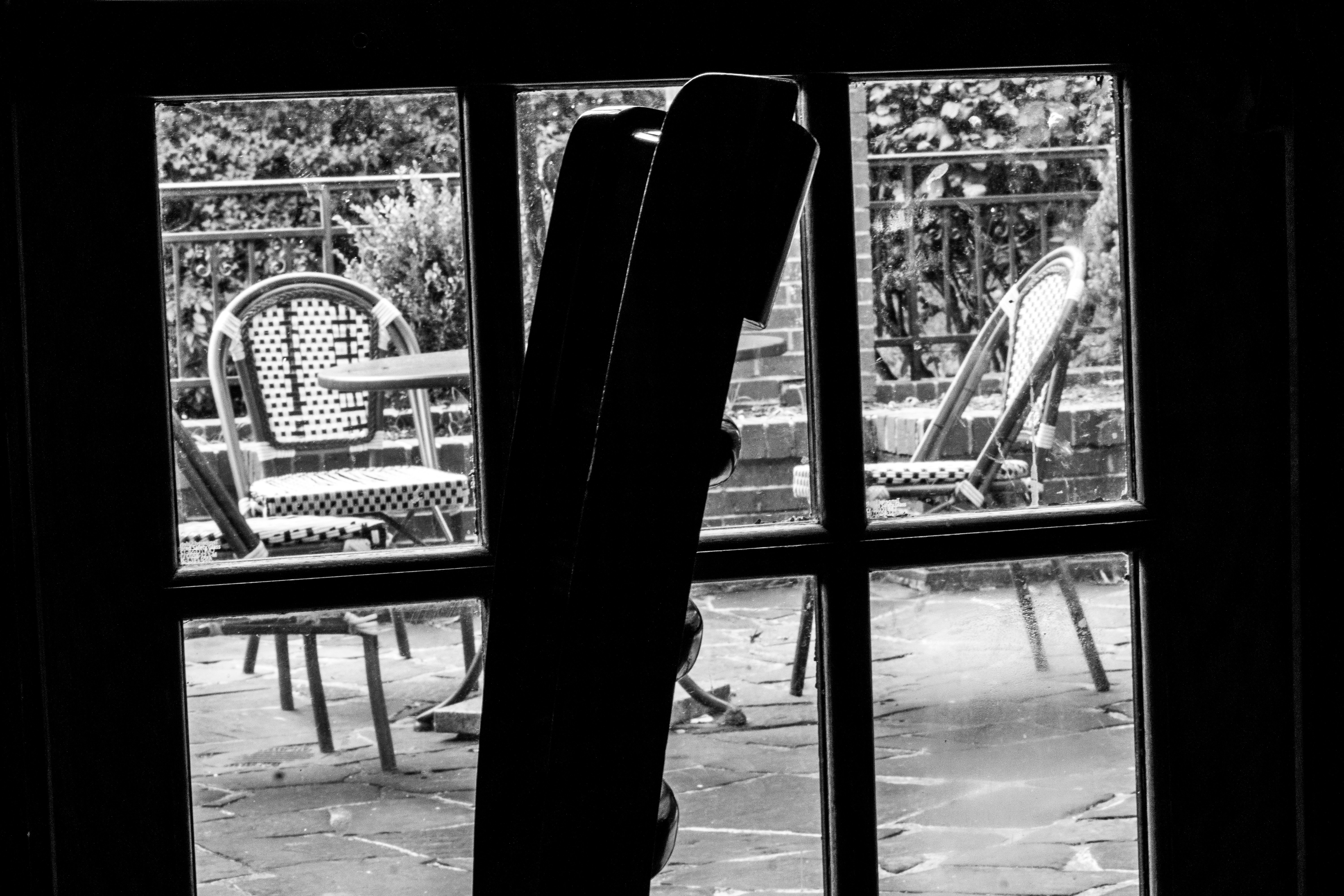 Gridded Window, Silent Patio: A Dark Silhouette Through Monochrome Glass