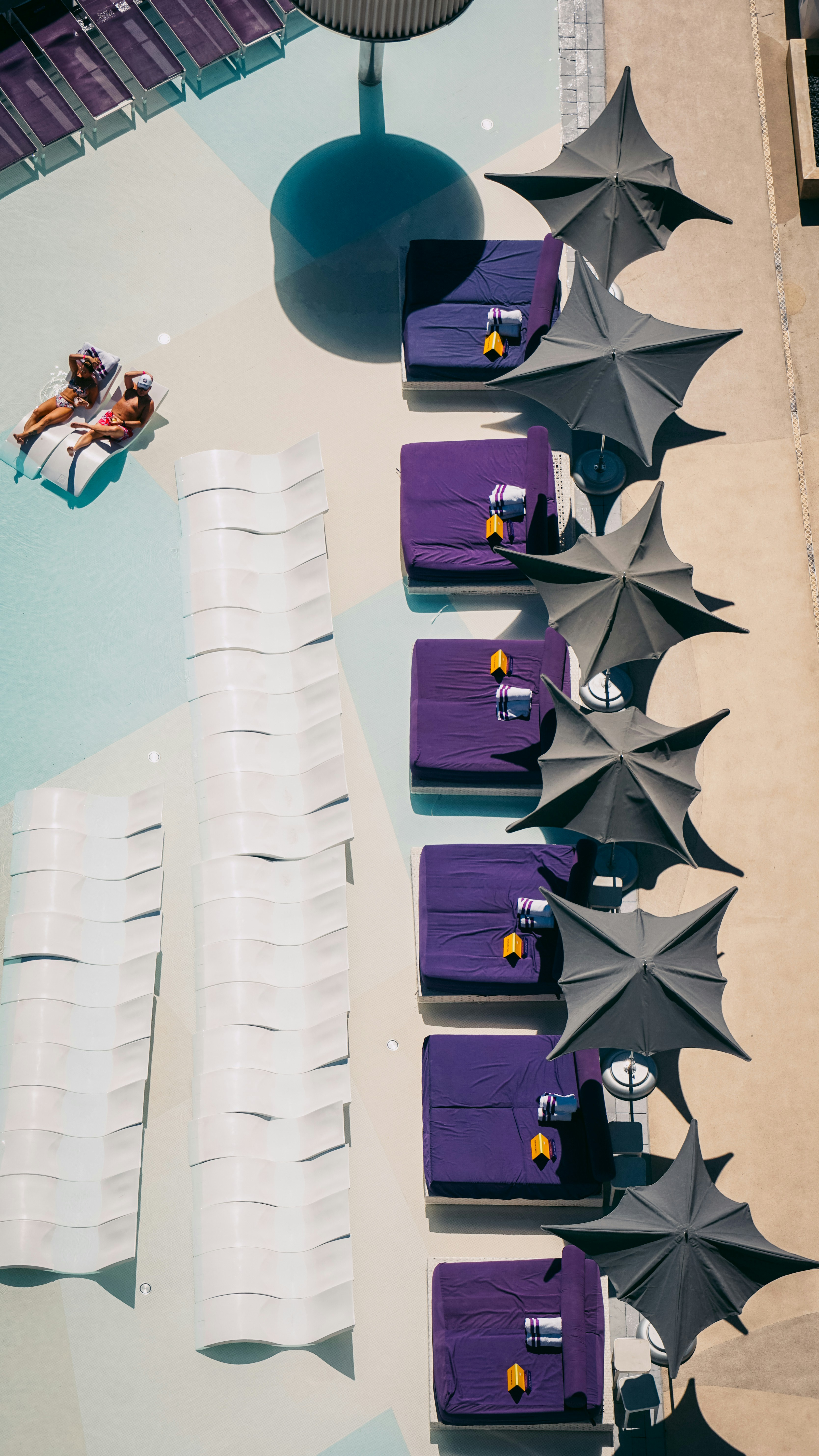 Poolside Geometry: Row of Purple Cushions Beneath Black Umbrellas