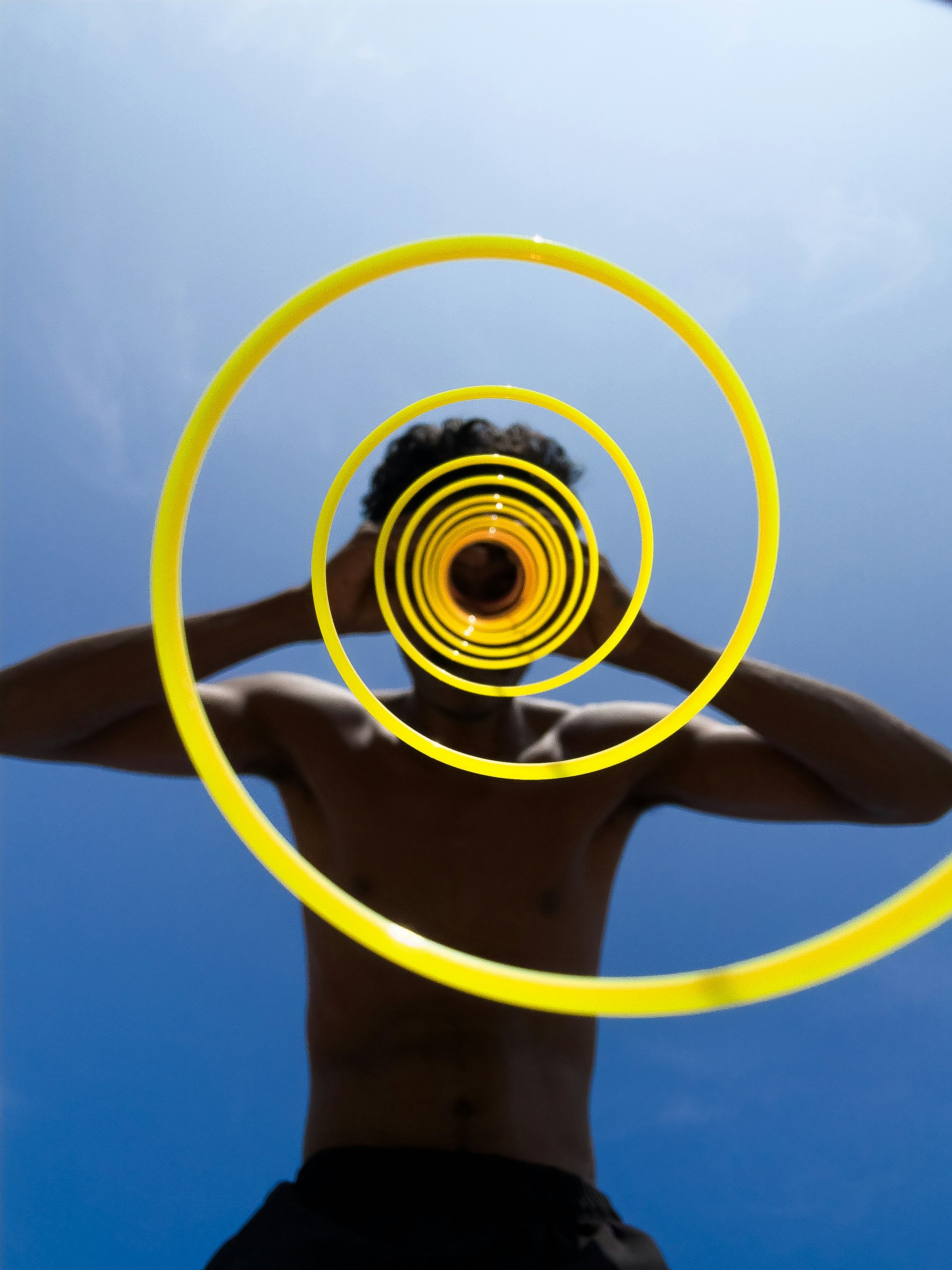  concentric rings: a silhouette through neon hoops under a blue sky