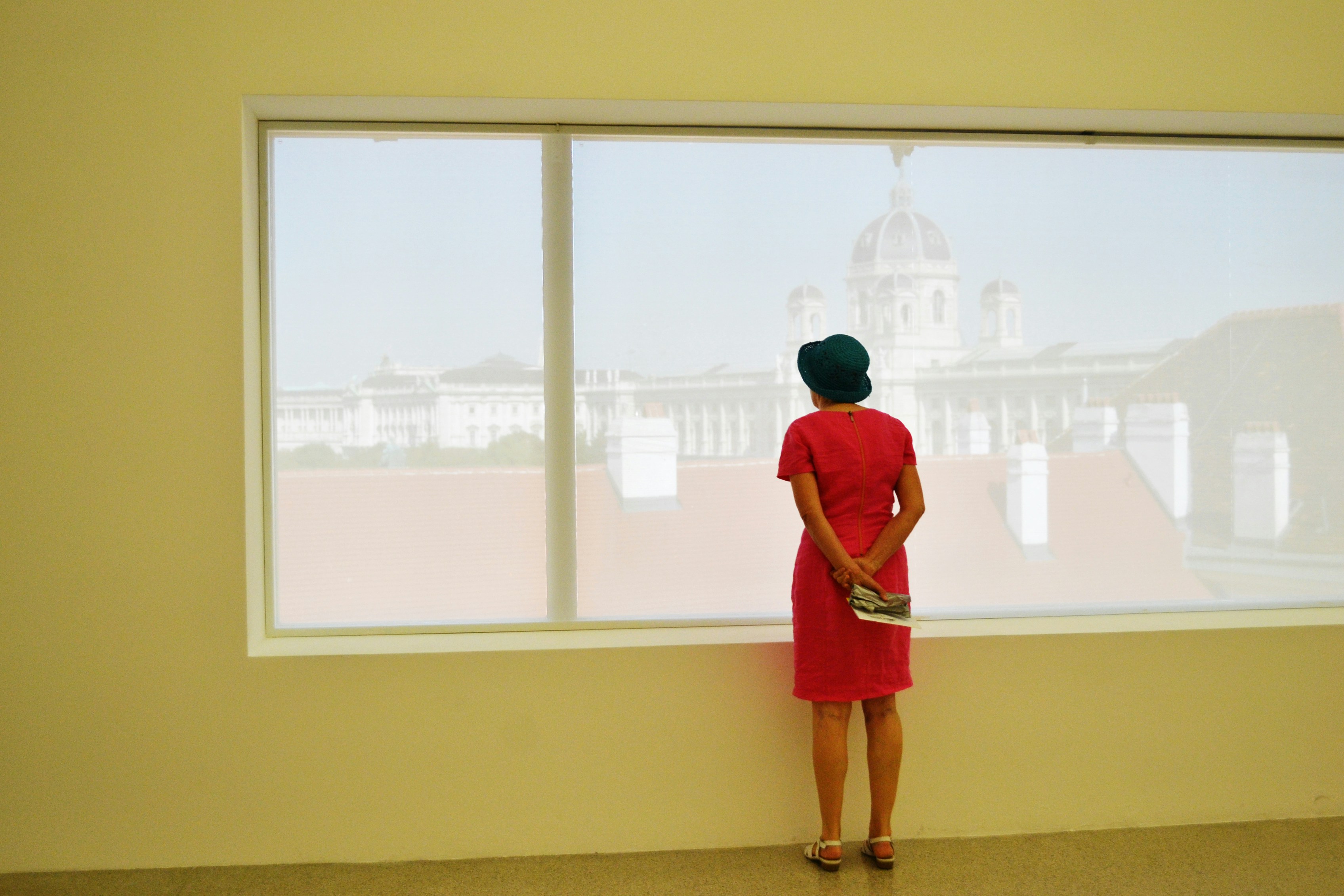 Woman looks out of a window at a distant building. photo – Free ...
