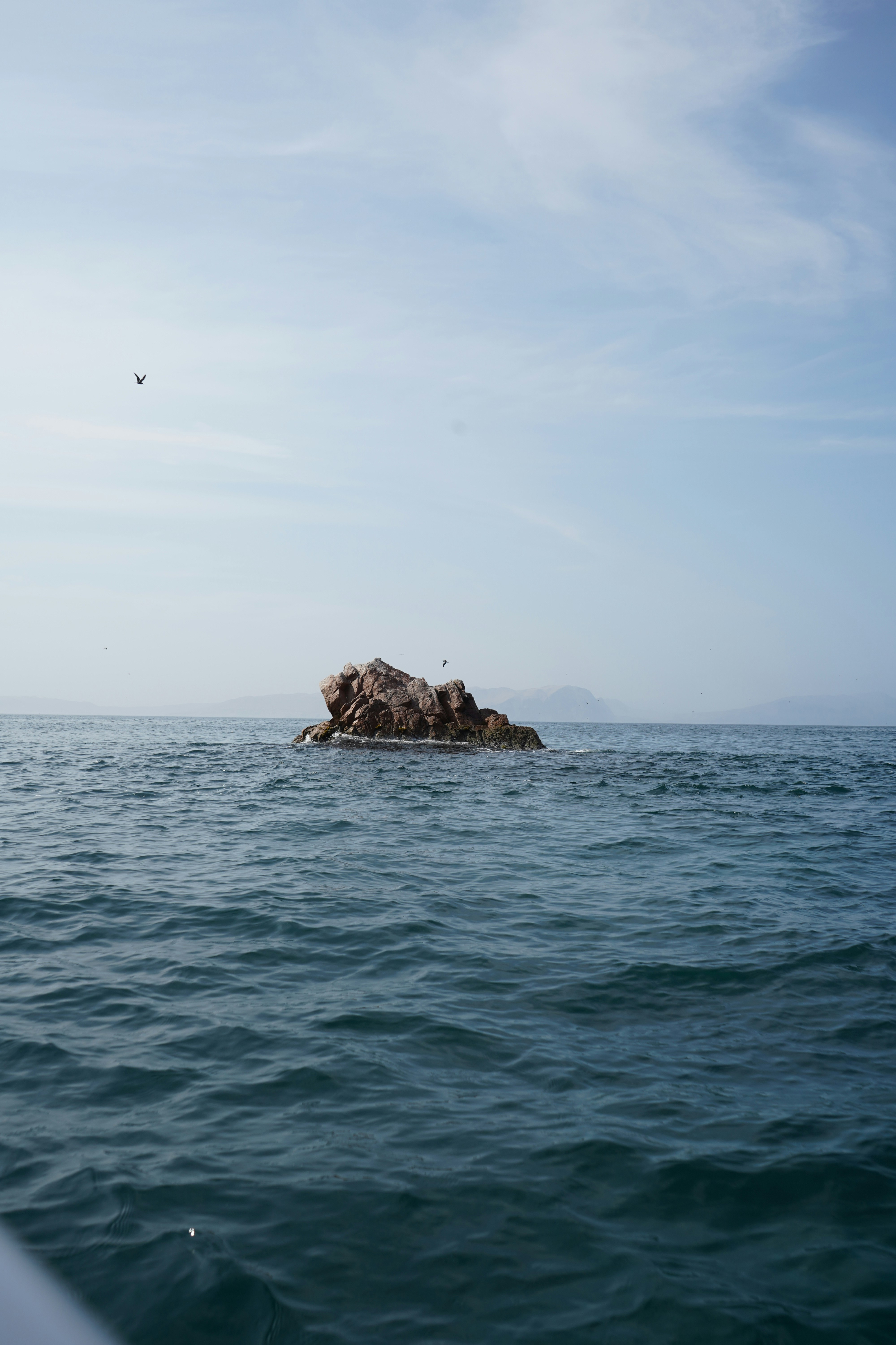 Isla rocosa que emerge de las tranquilas aguas del océano. foto ...