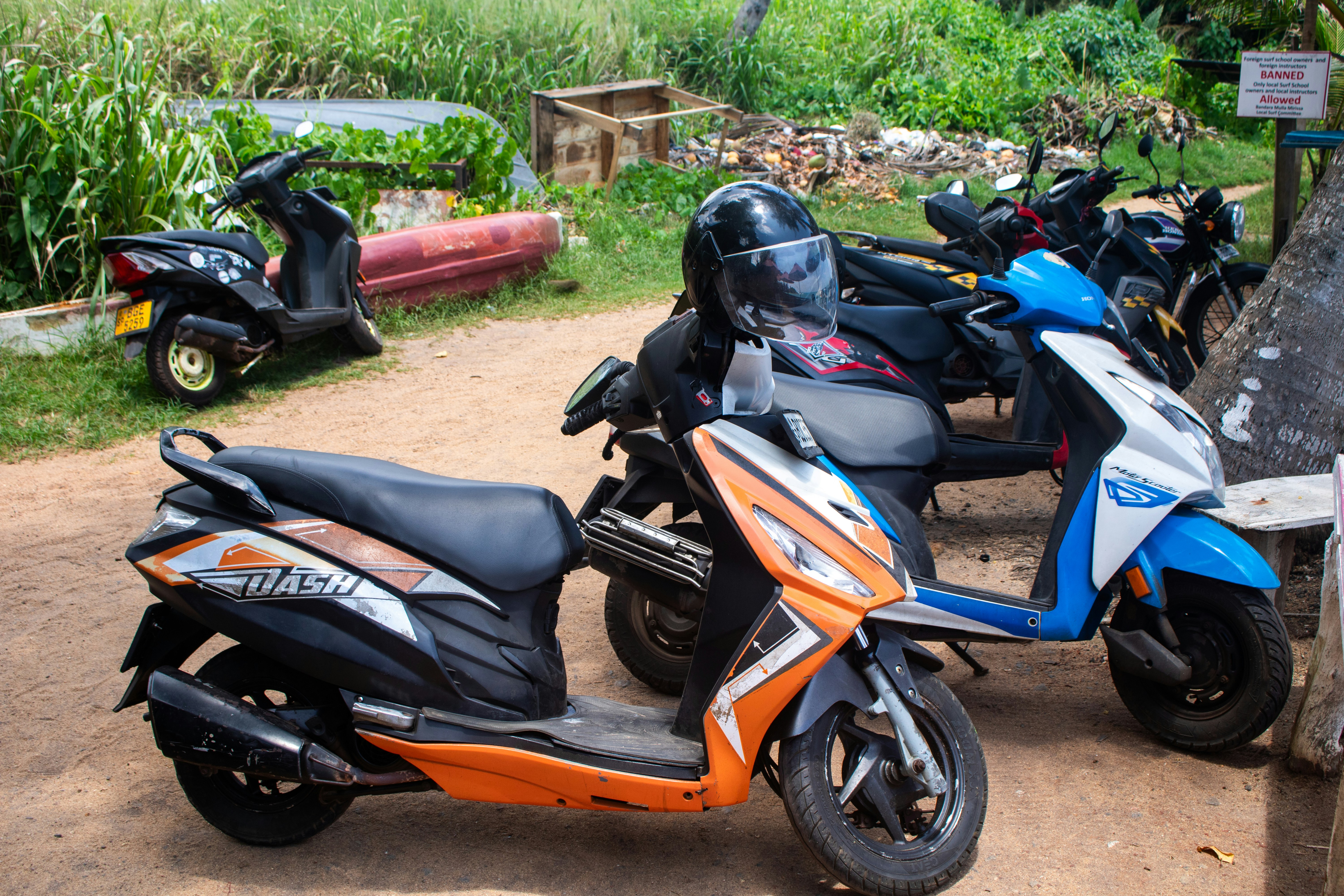 Sunlit Orange and Blue Scooter Row in a Rustic Parking Nook