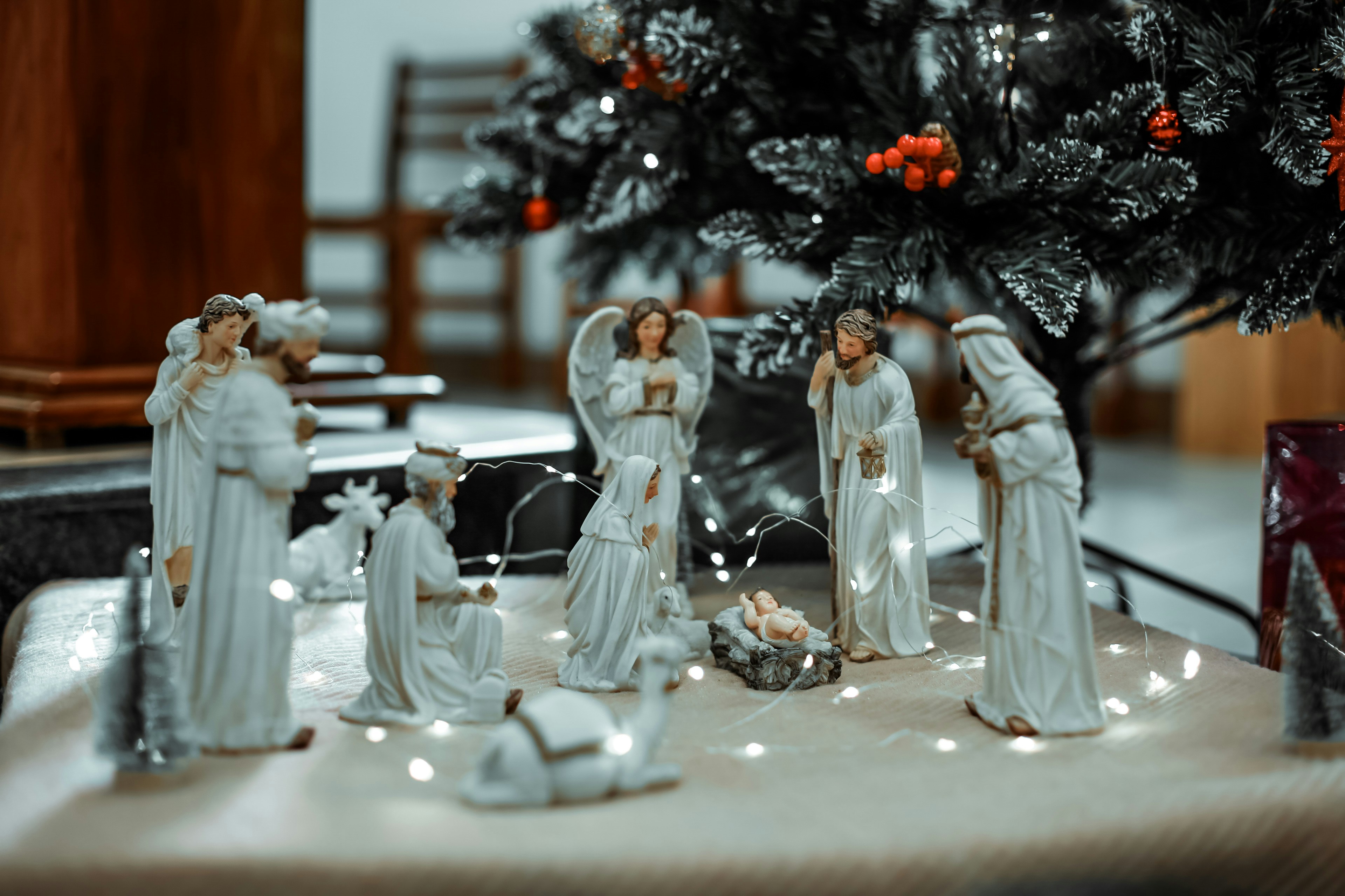 Intricate figurines depicting the Nativity scene surrounded by twinkling lights and a festive backdrop.